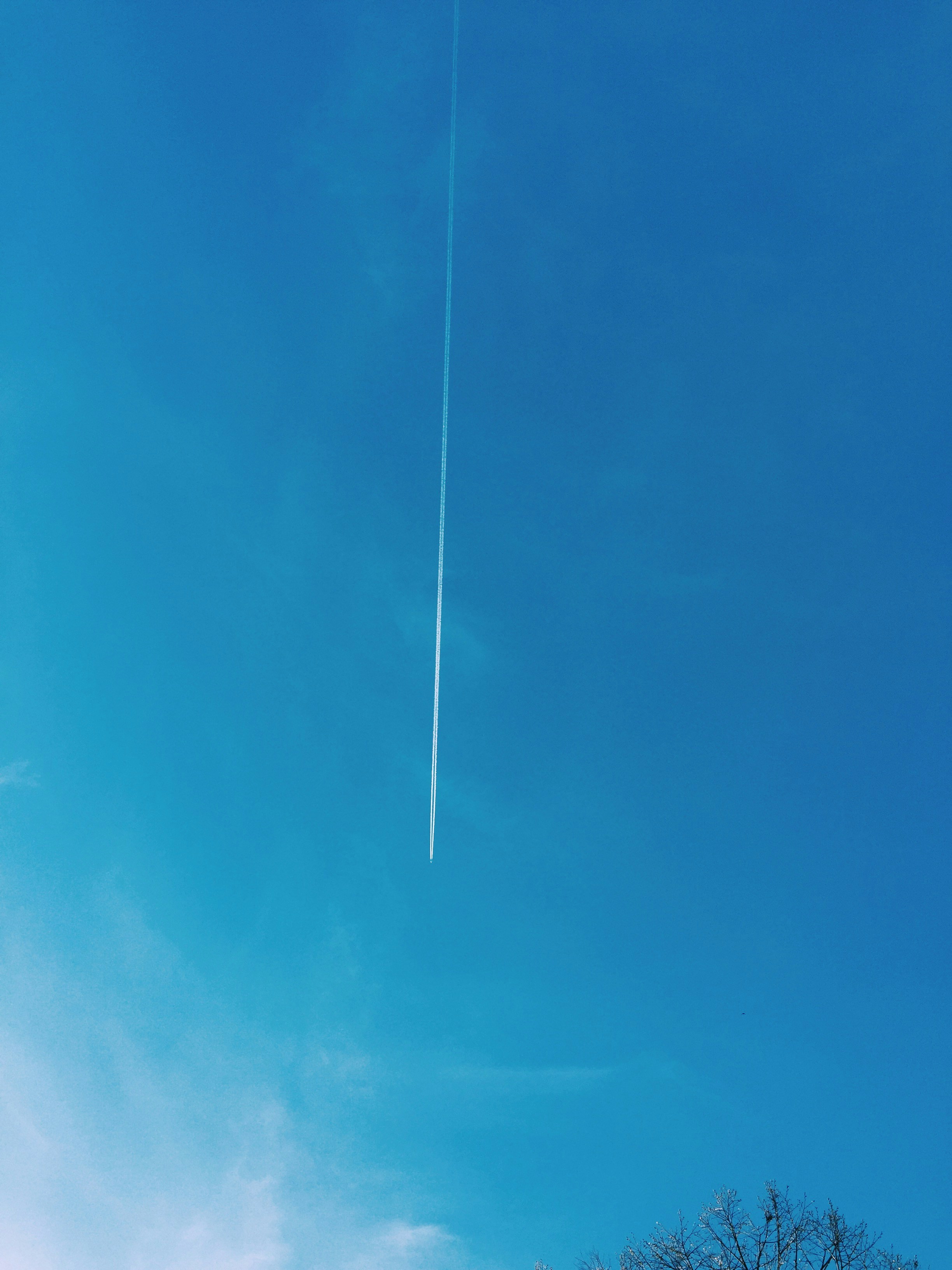 Contrail streaking across a clear blue sky, showcasing the vastness above. The scene captures the essence of flight and freedom.