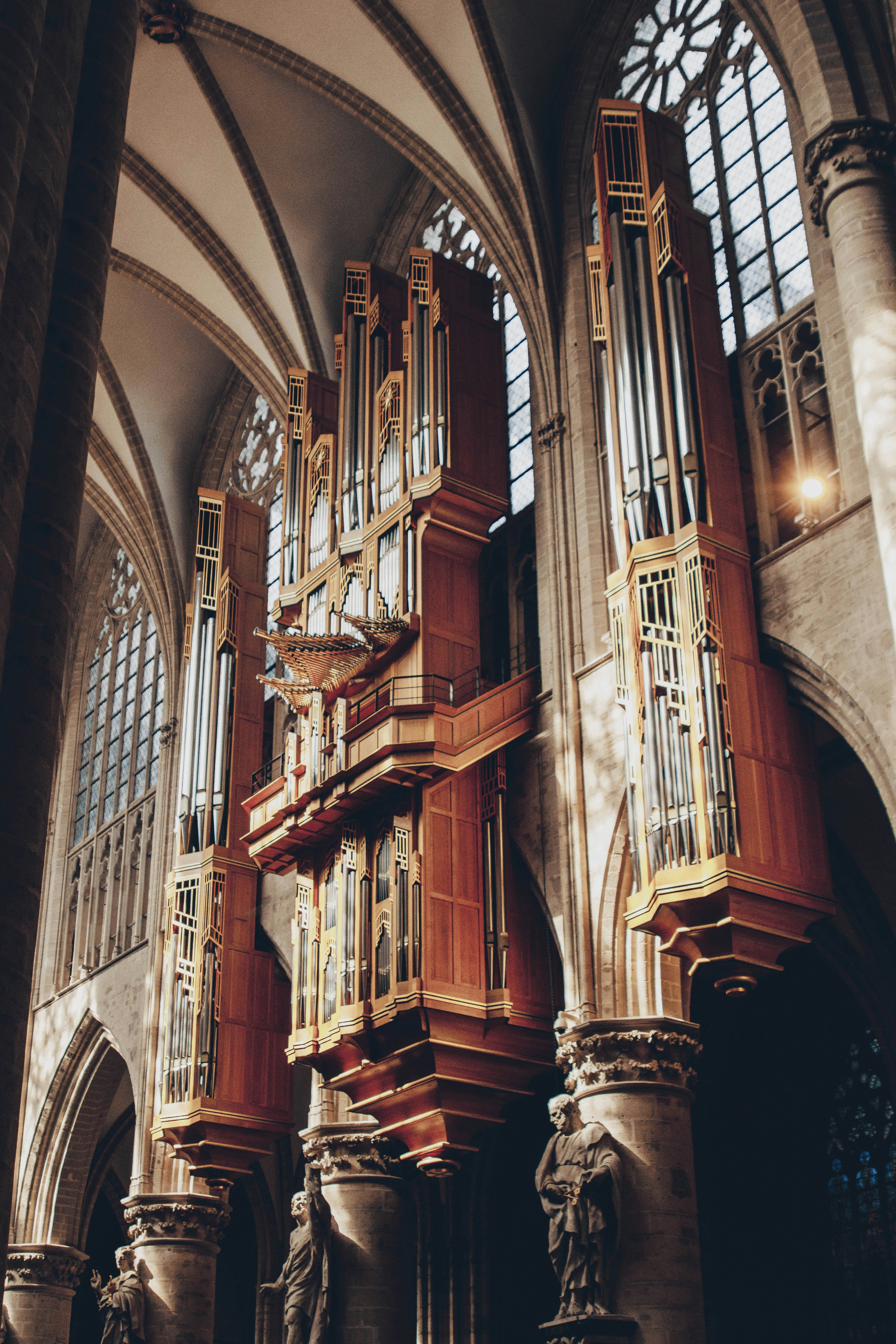 Elaborate organ installation within a Gothic cathedral, showcasing intricate woodwork and towering pipes against a backdrop of stained glass and stone architecture.