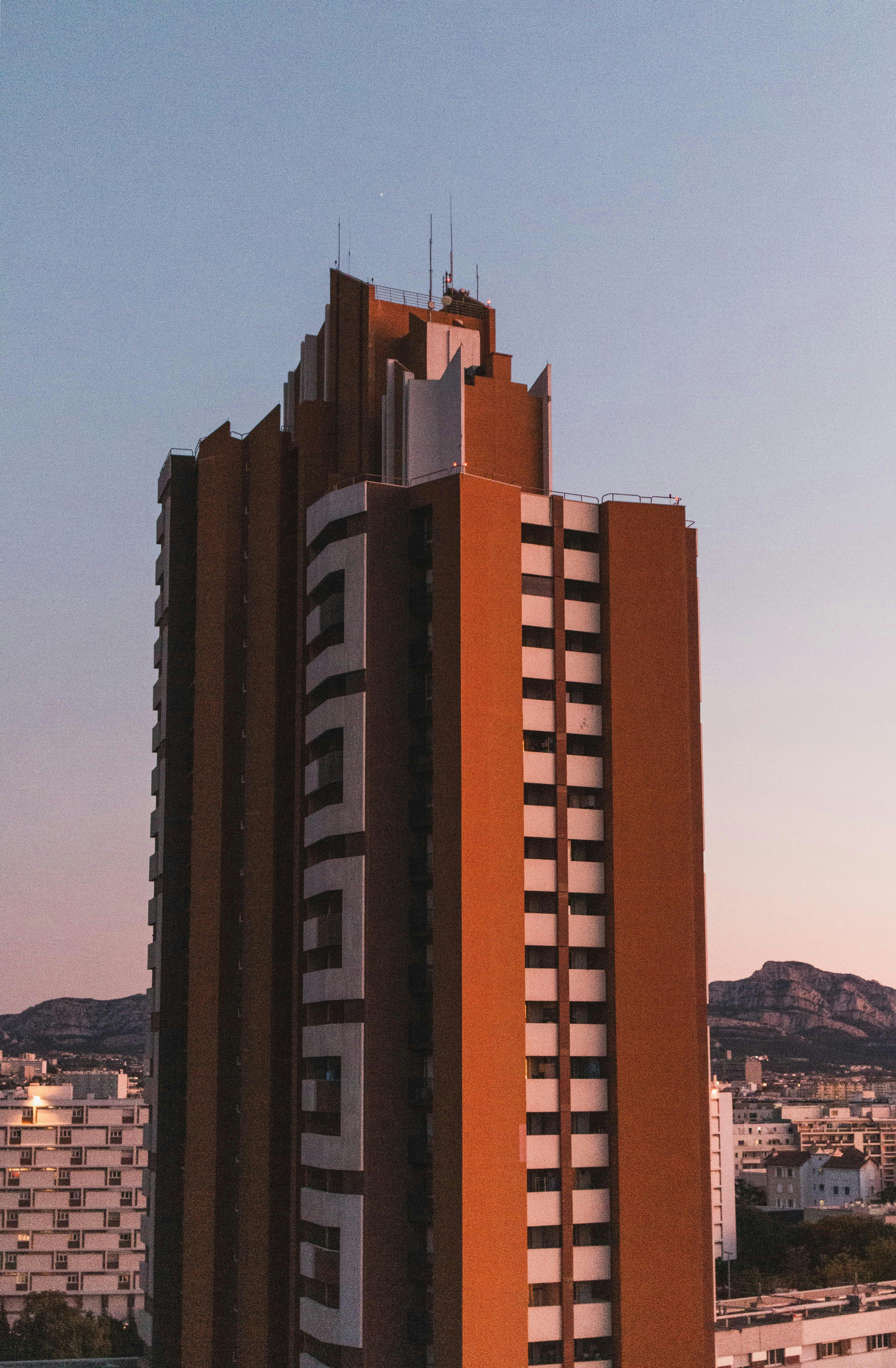 High-rise building with a striking facade under a twilight sky, showcasing architectural lines and urban landscape.