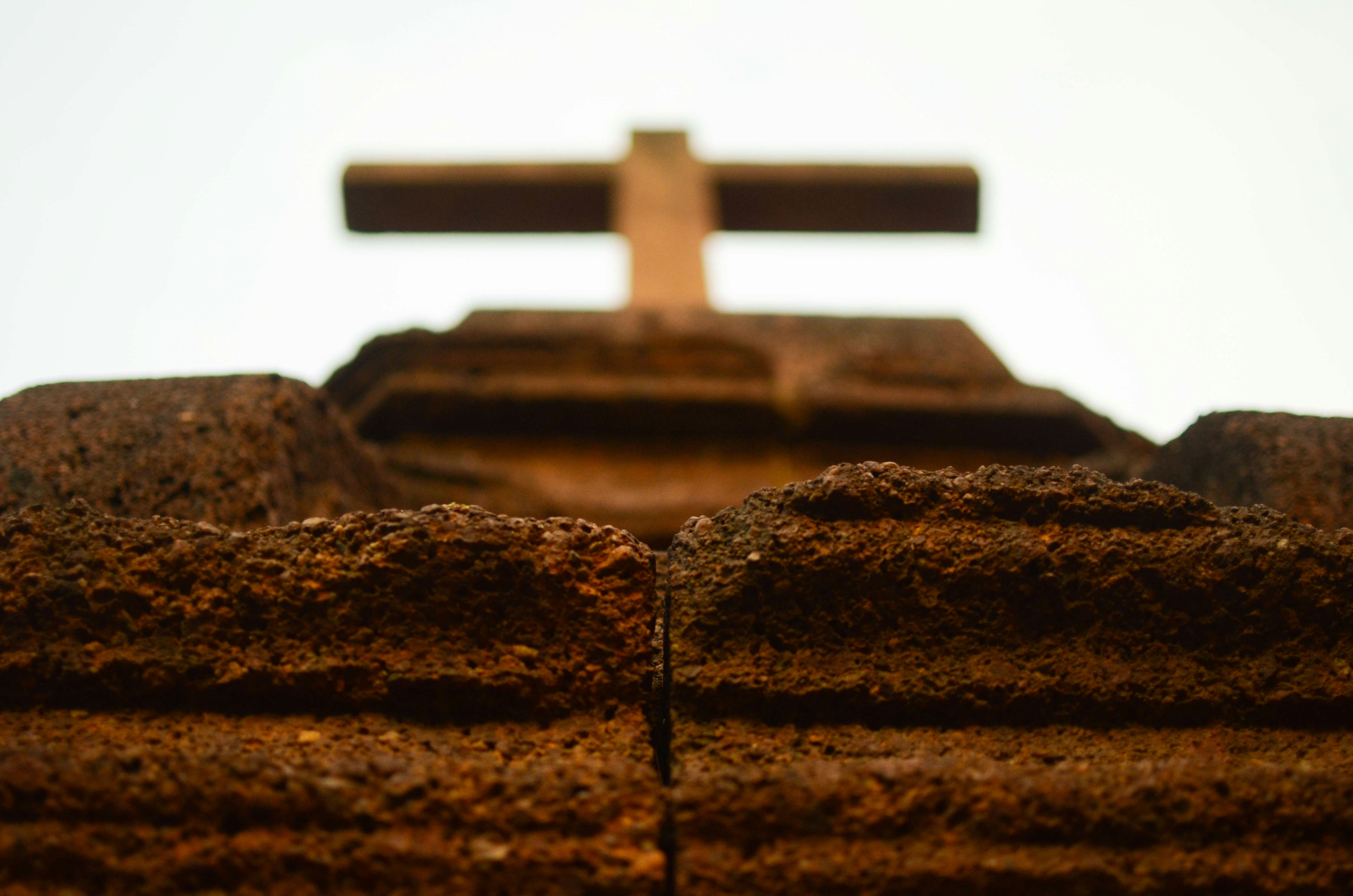 Brickwork Ascends Toward a Distant Cross under a Muted Sky
