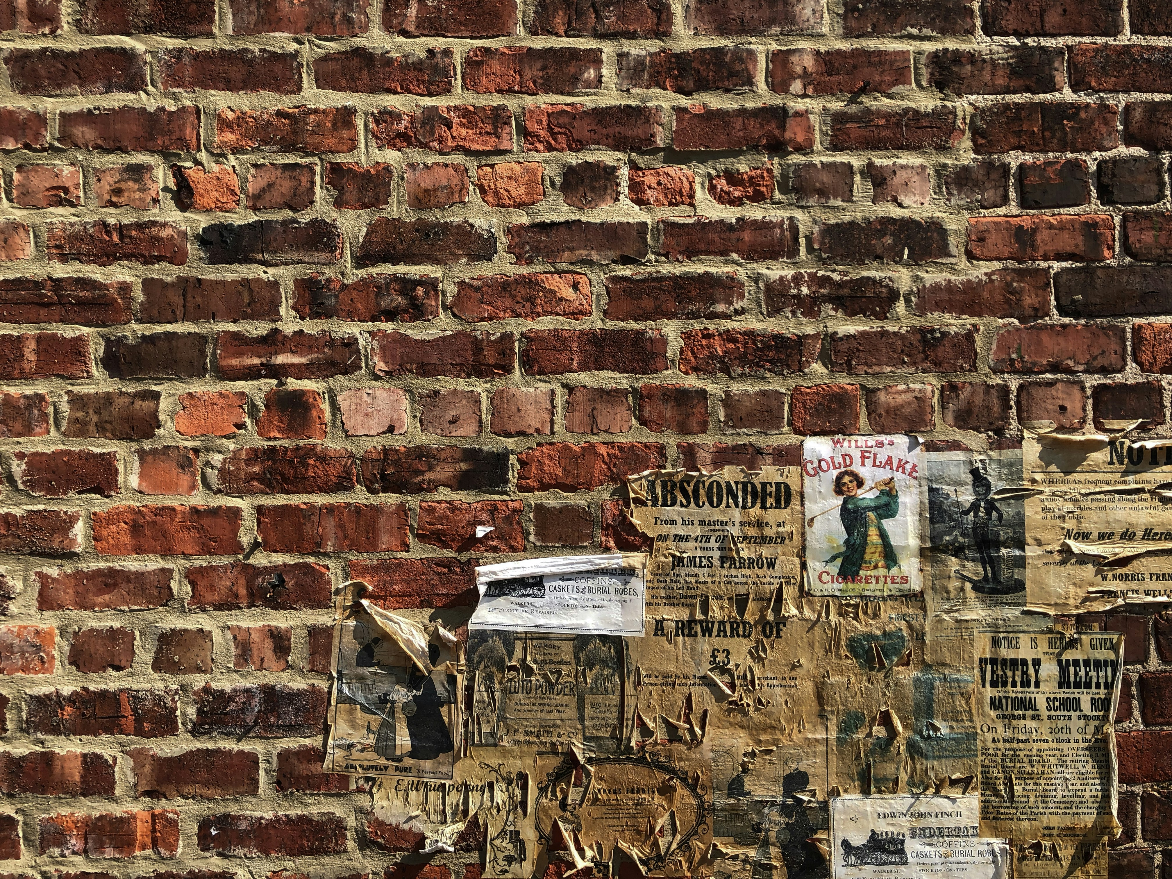 A brick wall with a bunch of newspaper on it photo – Free Wall Image on ...