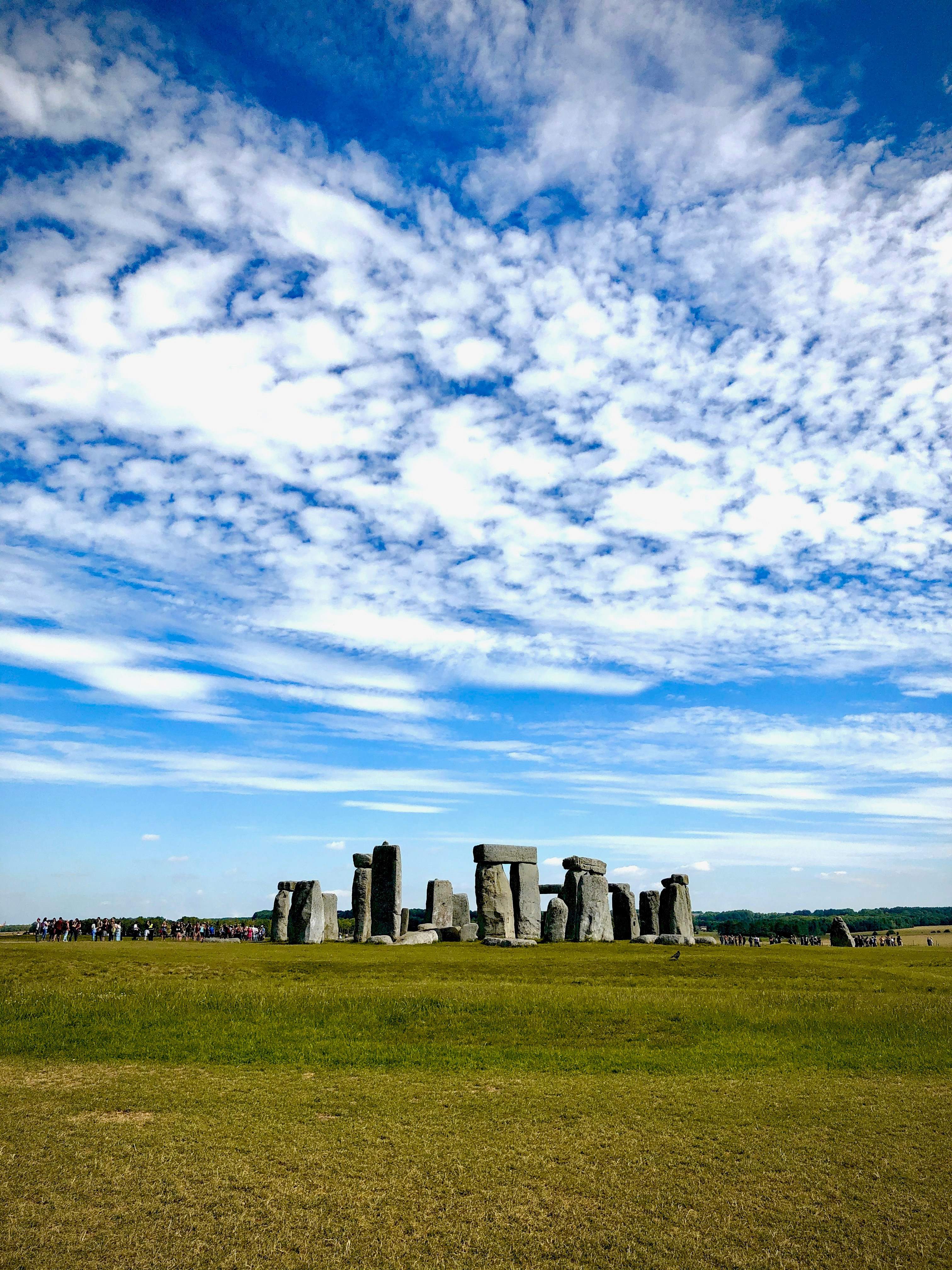 Stonehenge under a vibrant blue sky with scattered clouds.