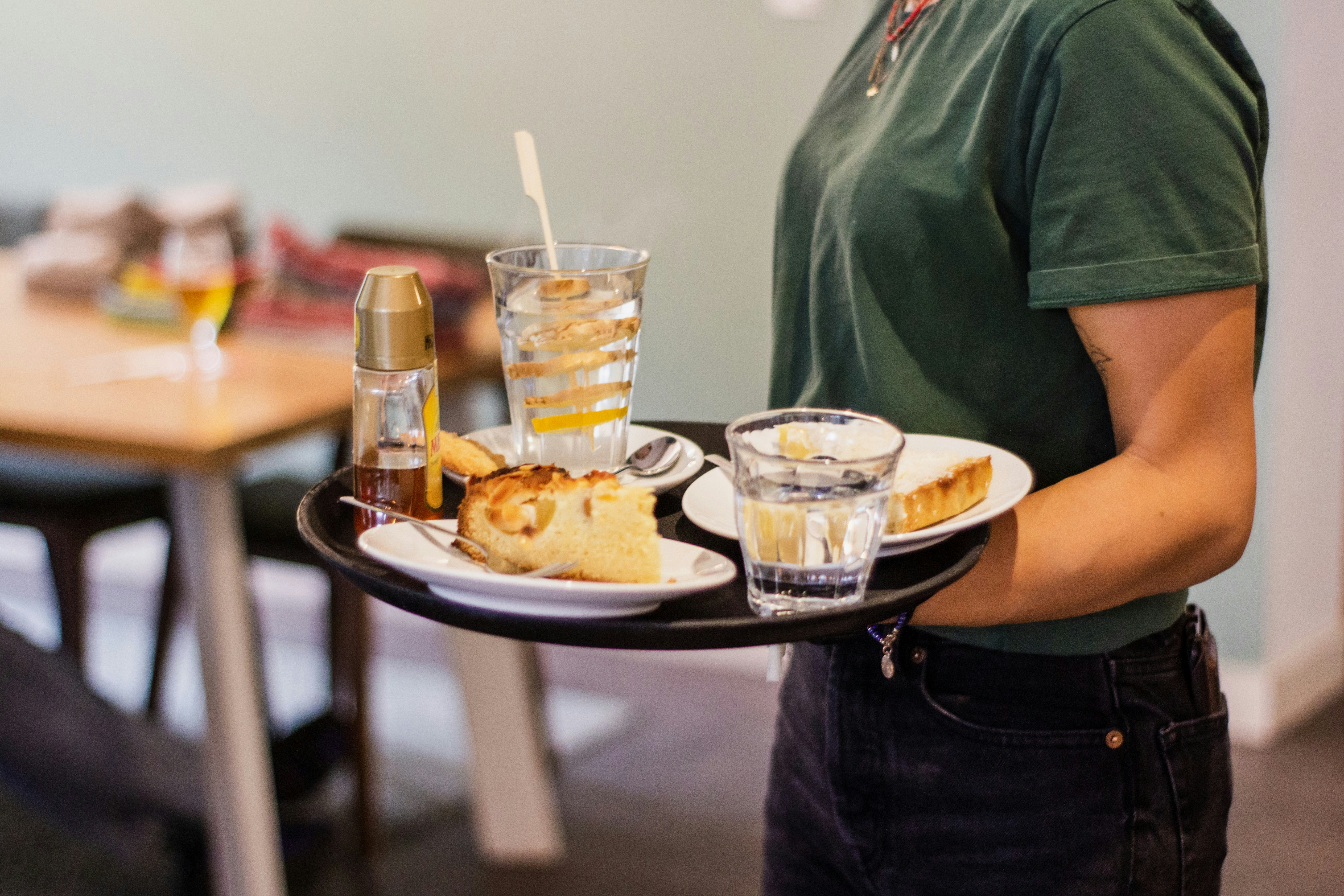 person holding tray with sliced of cake and water