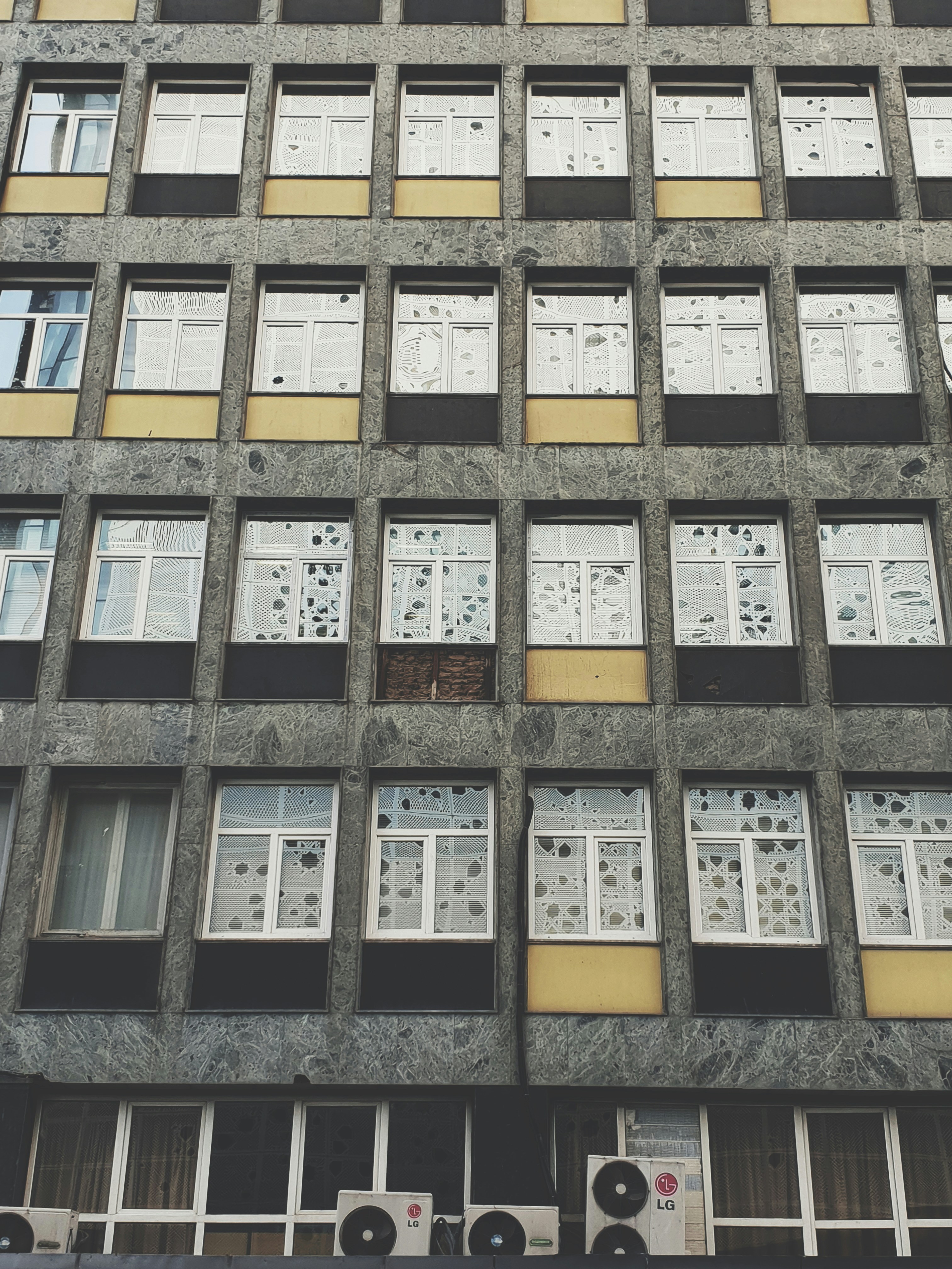 Grid of Glass and Concrete: Quiet Yellow Accents in a City Facade