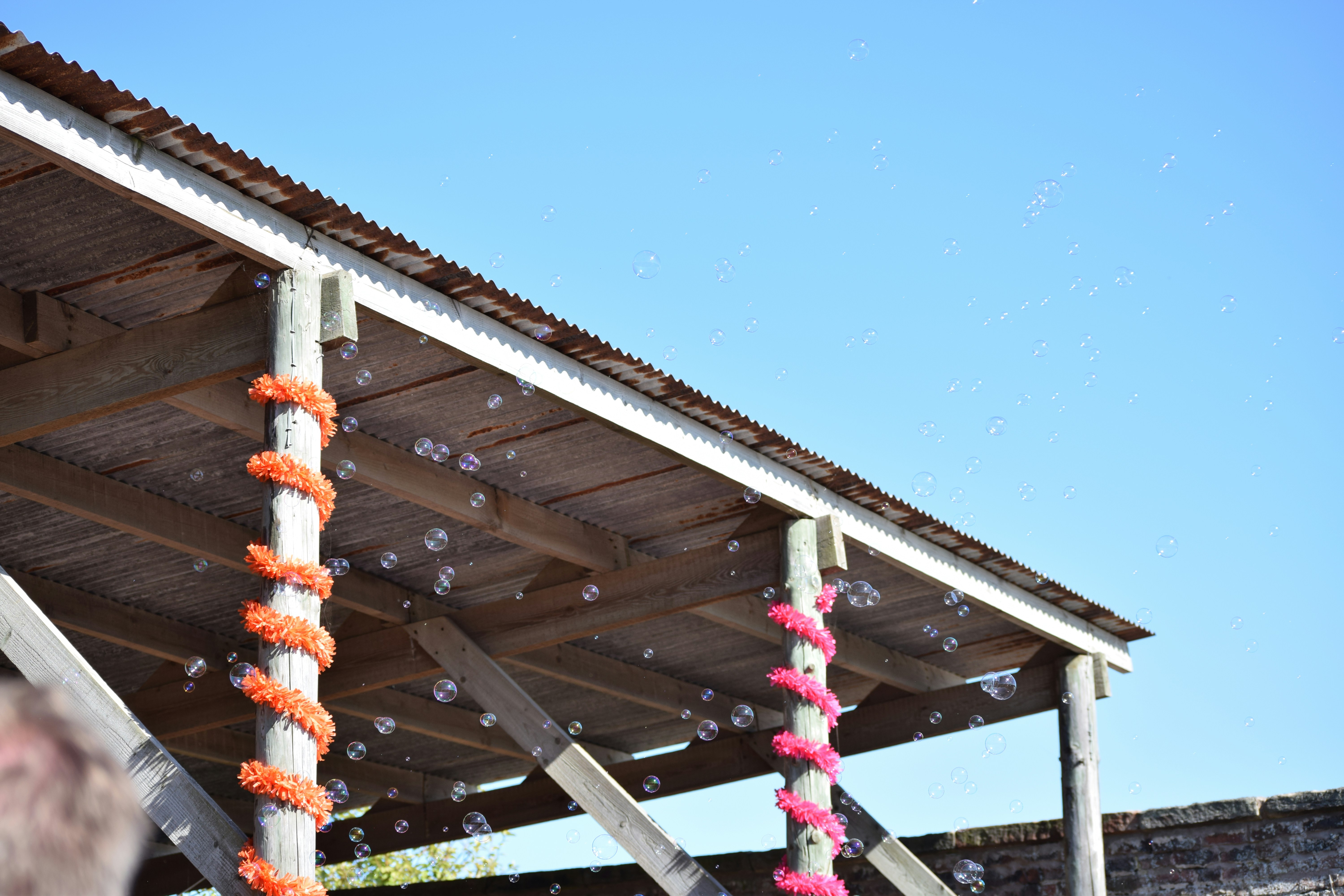 Colorful garlands on a sunlit wooden structure under a clear blue sky