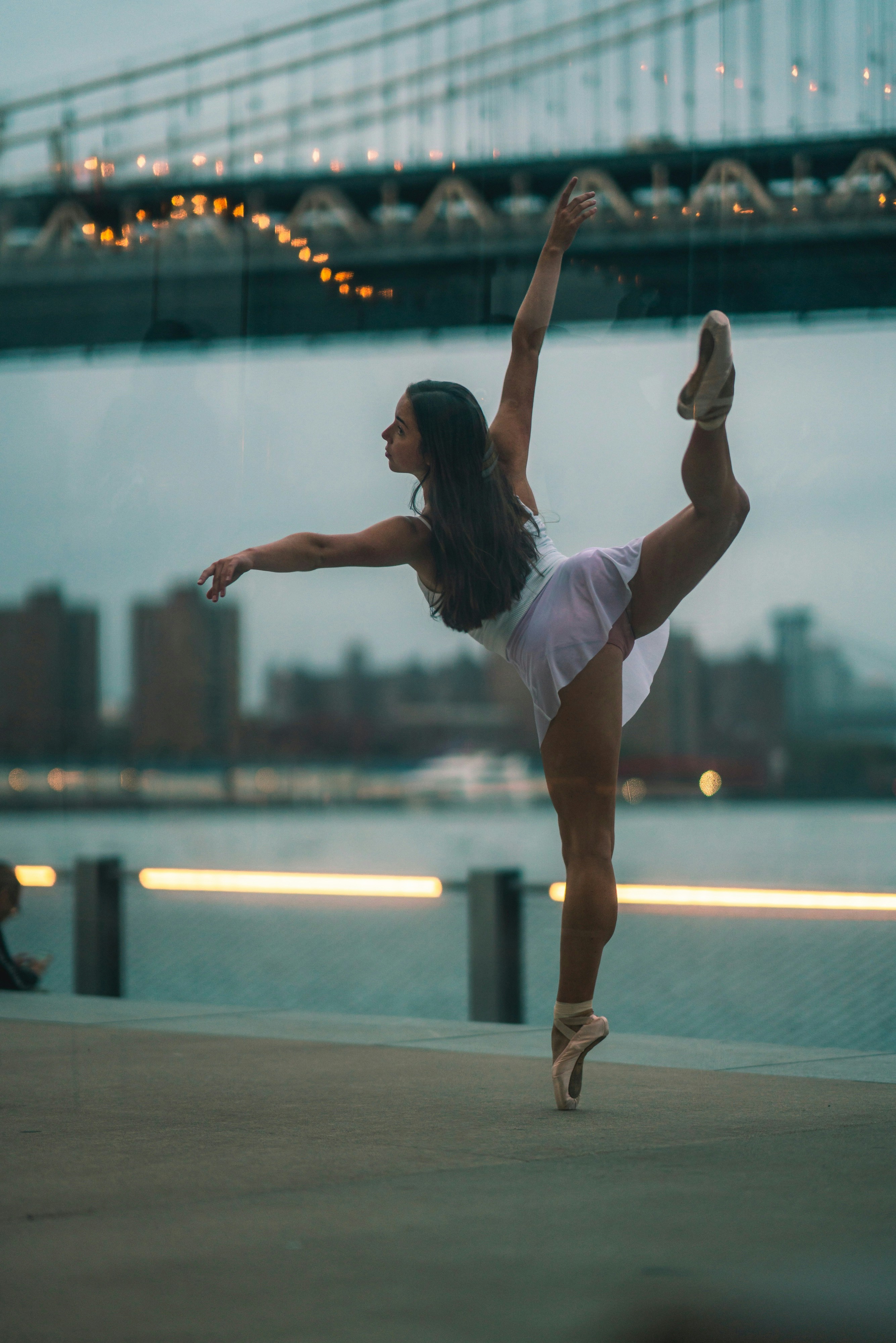 Ballerina standing on one foot tiptoeing at the city bay during day ...