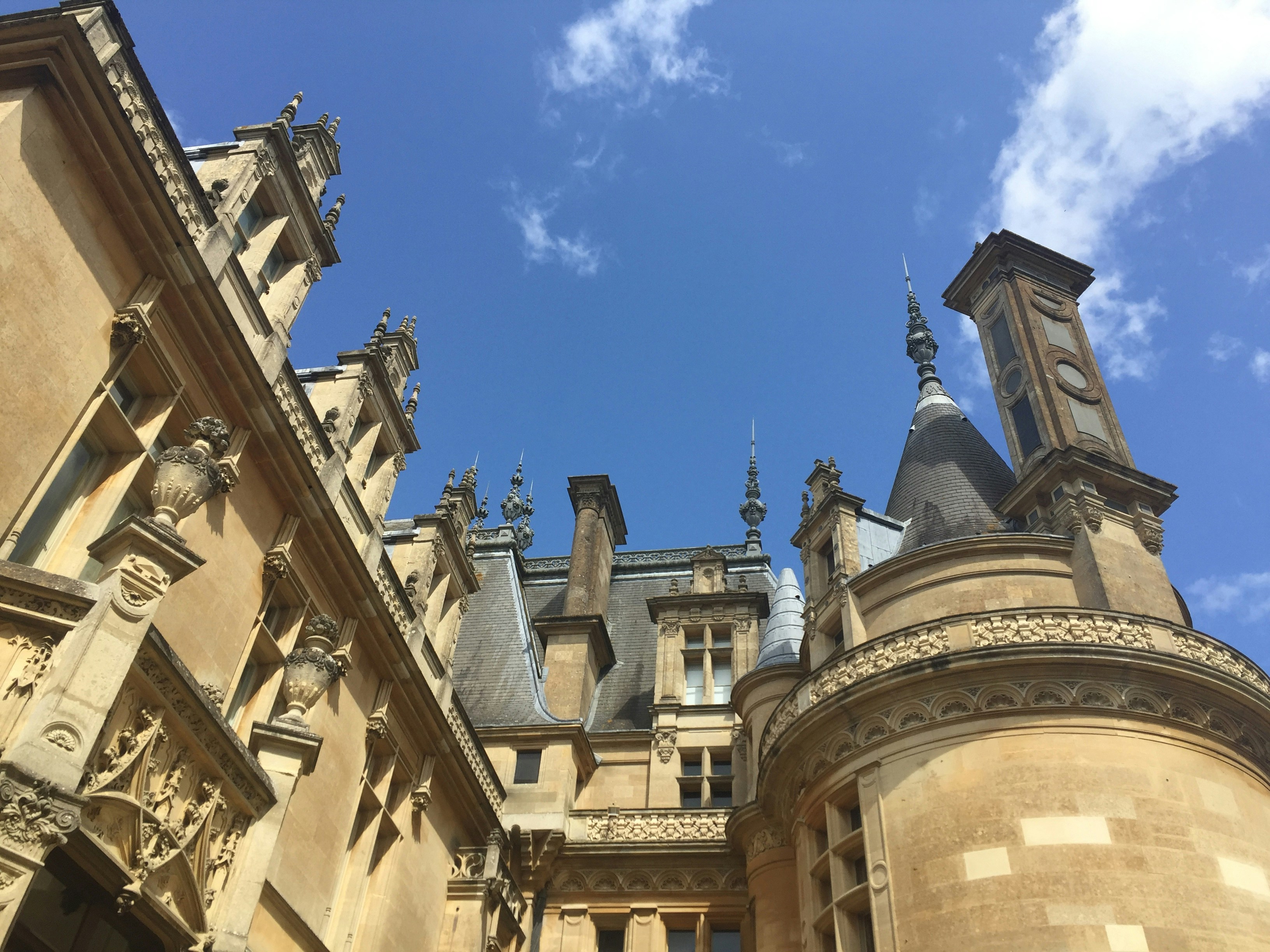 Intricate architectural details of a historic building against a bright blue sky, showcasing a blend of gothic and classical styles.