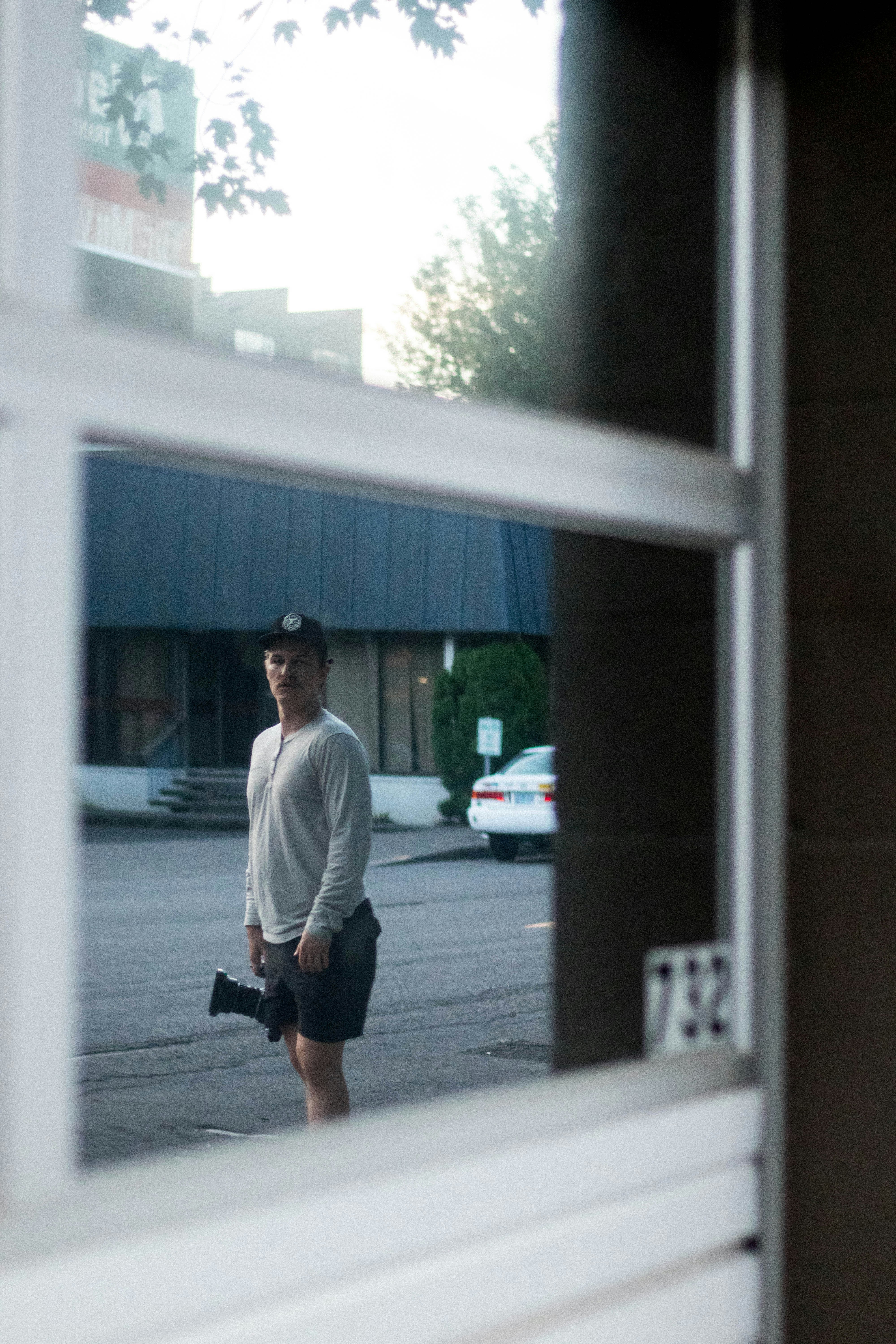 The Photographer in the Parking Lot: A Quiet Portrait Through a Shop Window