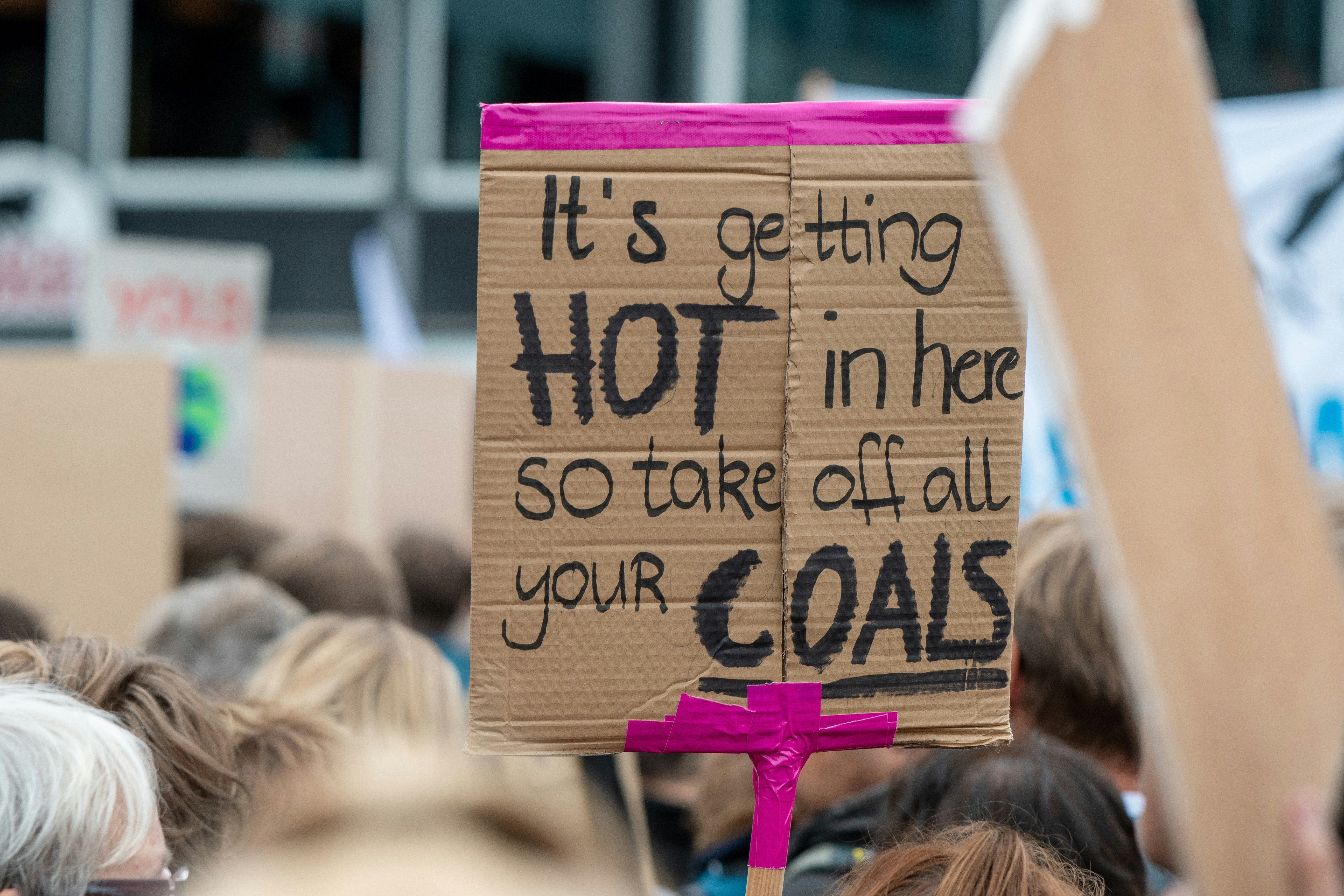 Person holding a sign with It's getting hot in here so take off all you ...