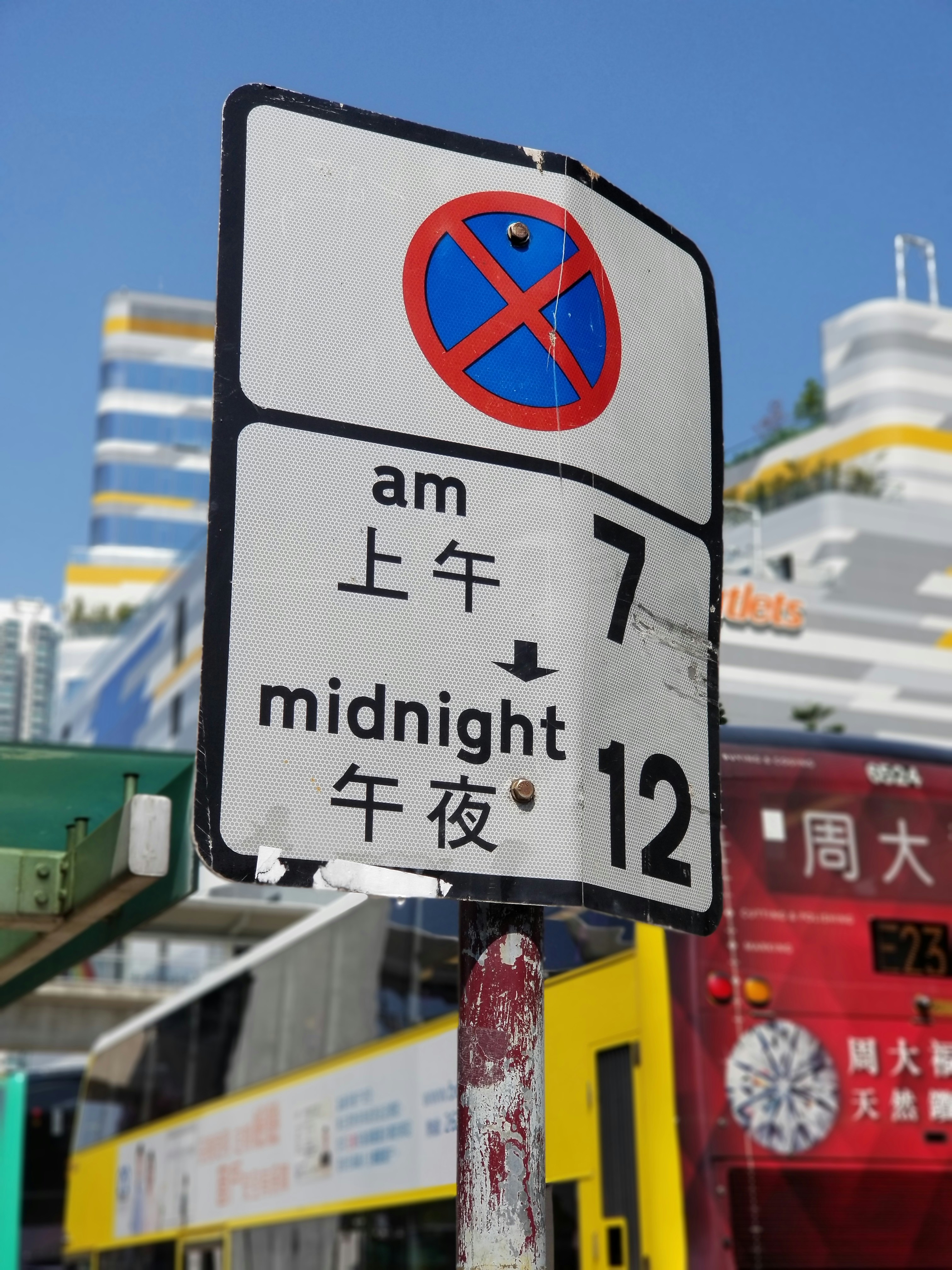 No parking sign indicating specific hours in both English and Chinese, set against a bustling urban backdrop.