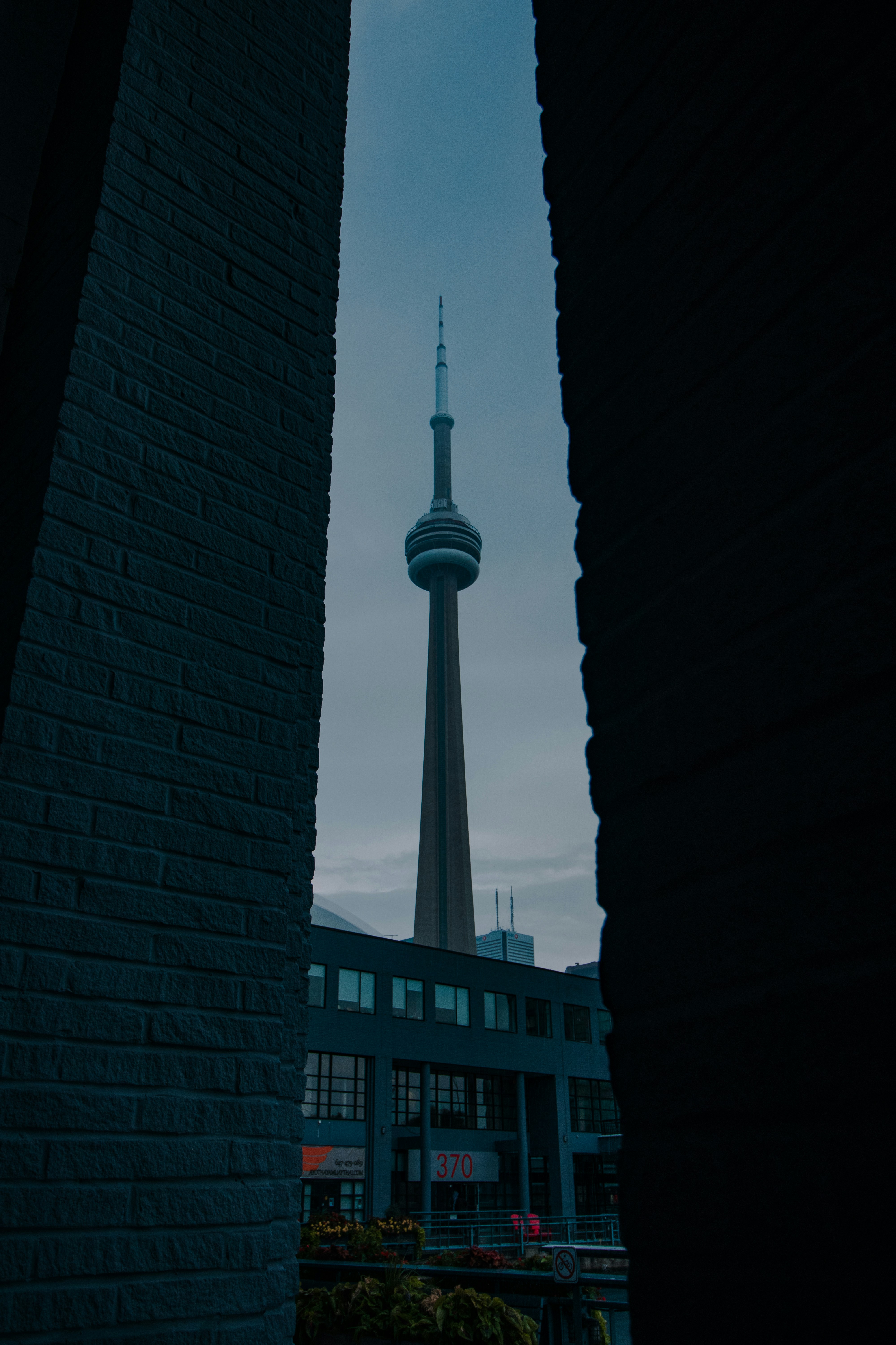 Edge of Light: CN Tower Framed Between Brick Walls at Blue Hour
