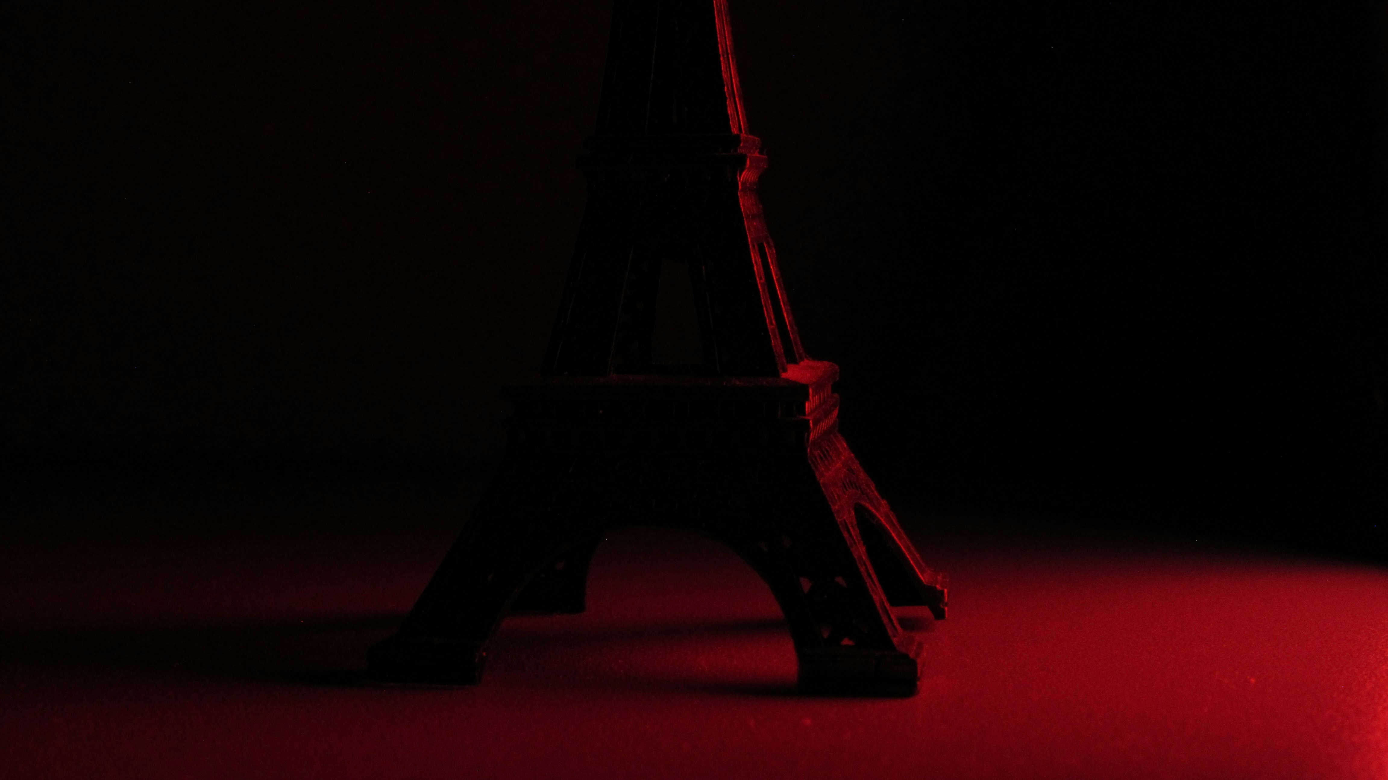 Eiffel Tower replica cast in deep red light, creating a dramatic shadow effect on a dark background.