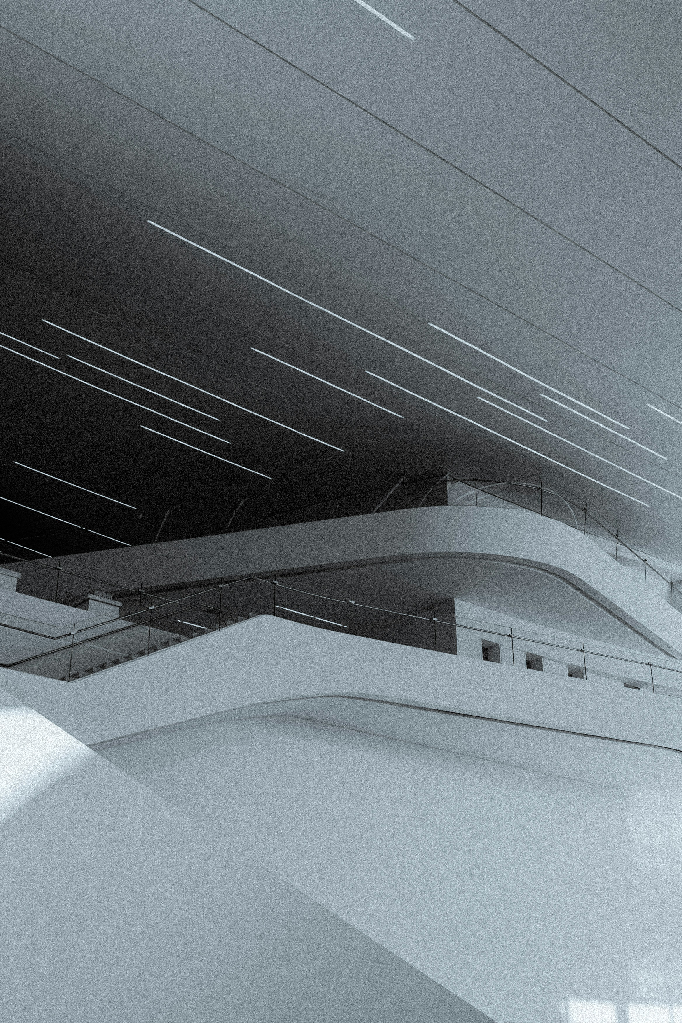 Long-exposure night photograph of a modern white building with curved balconies, as streaking light trails cross a dark sky.