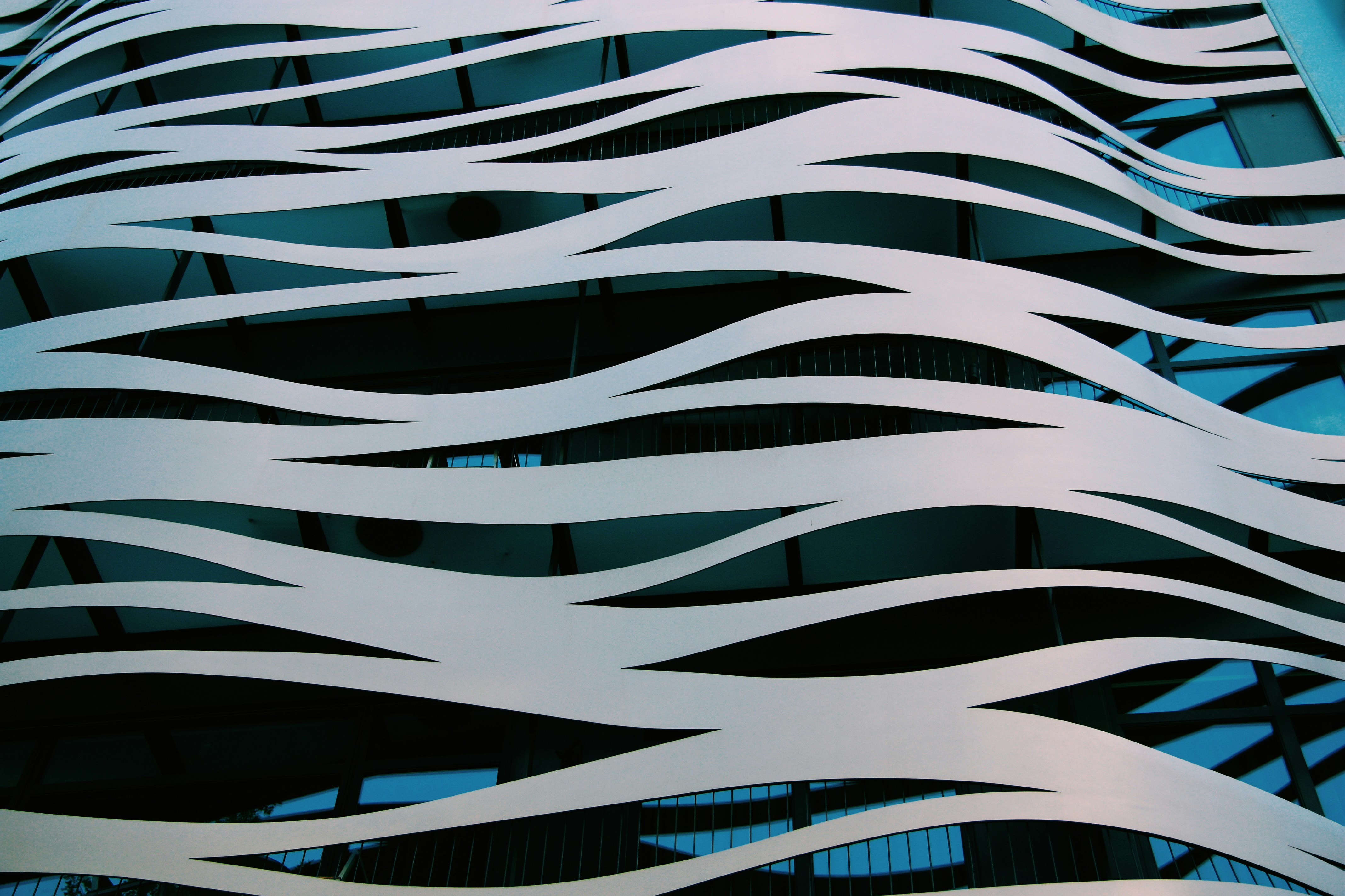 Abstract architectural facade with wavy patterns and reflective windows.