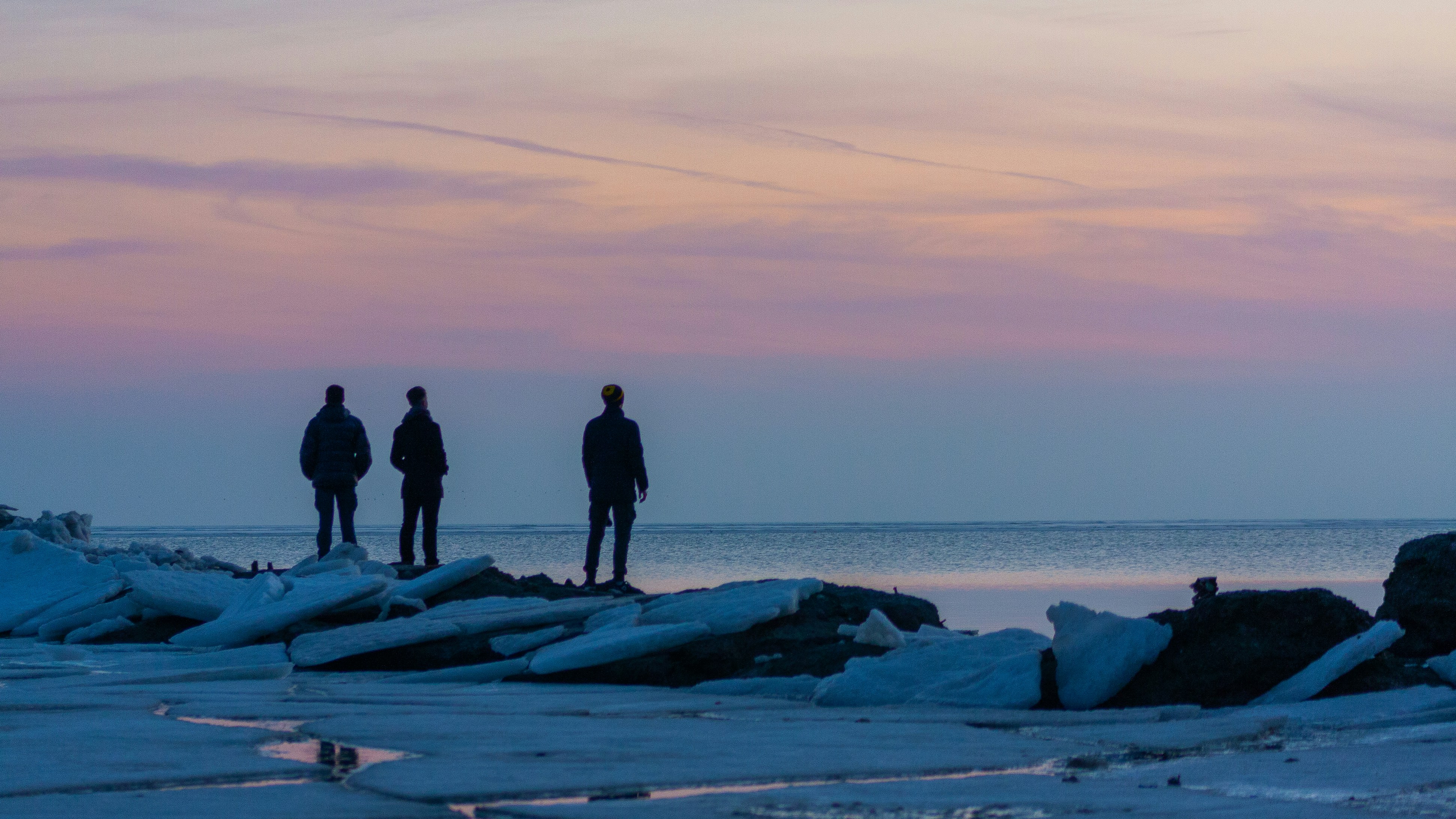 Three Silhouettes on a Frozen Shore at Dusk