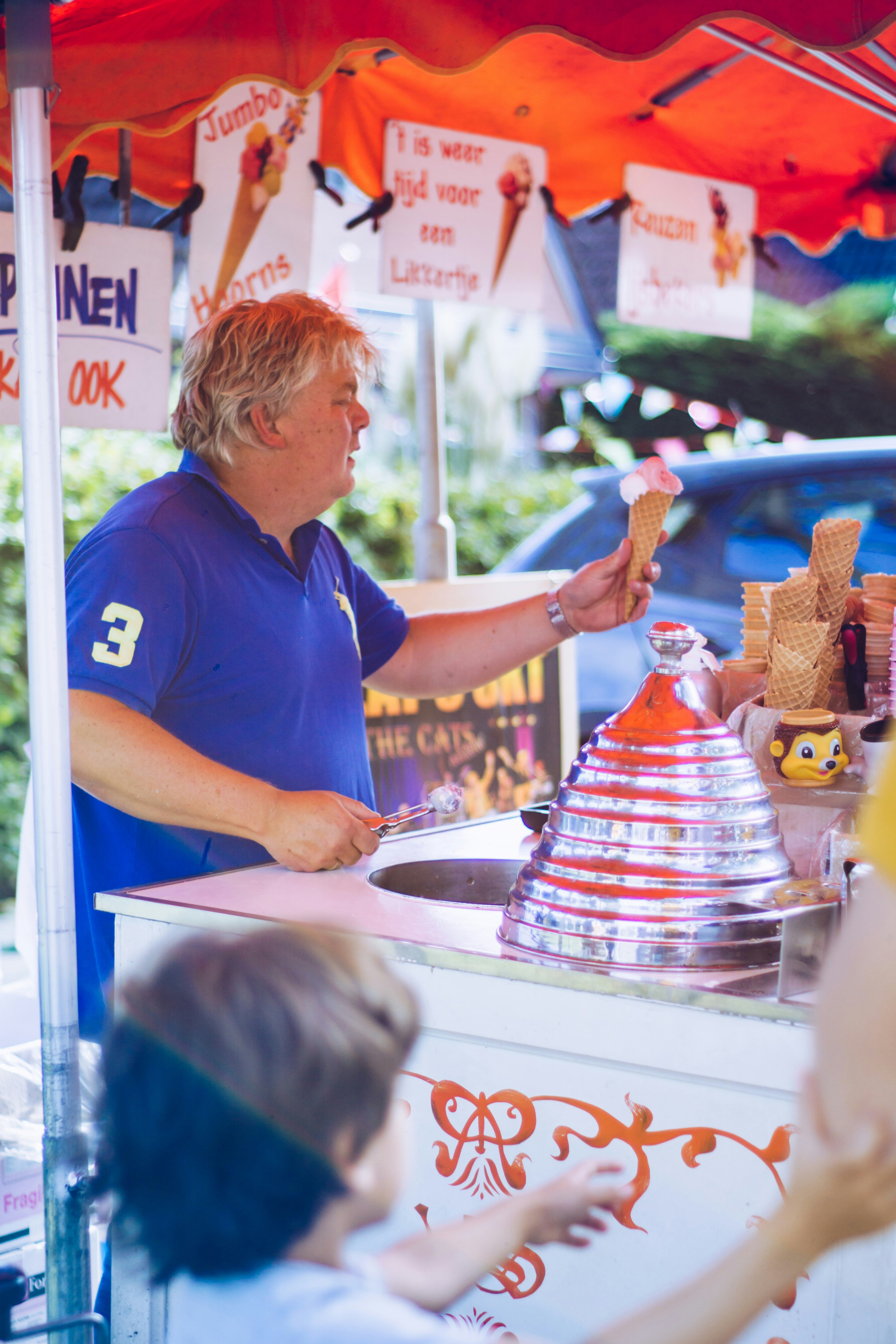 Vendor in a festive fair stall serving ice cream cones