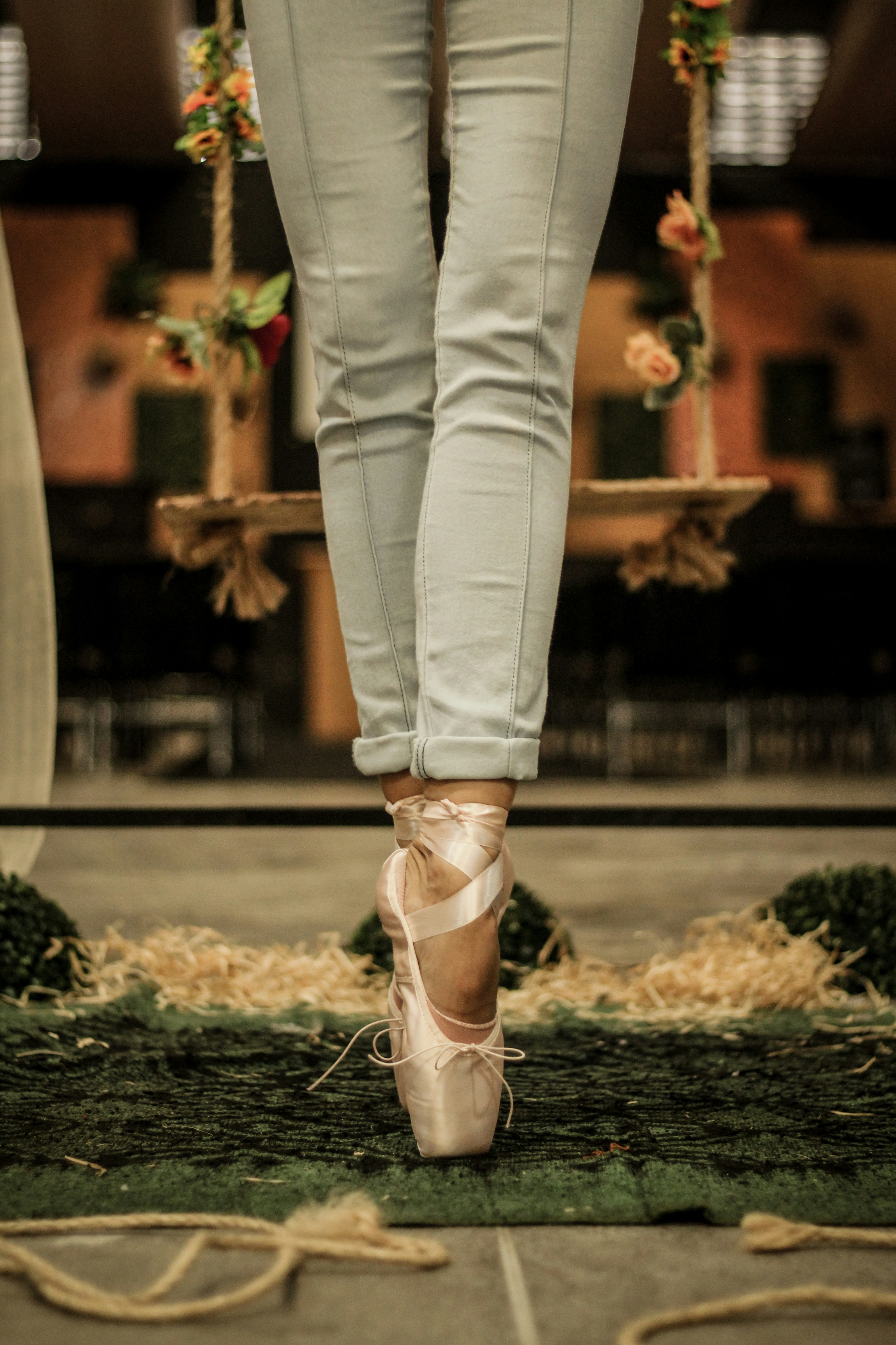Ballet dancer poised on pointe, showcasing graceful leg and delicate ballet shoes against a rustic backdrop. 