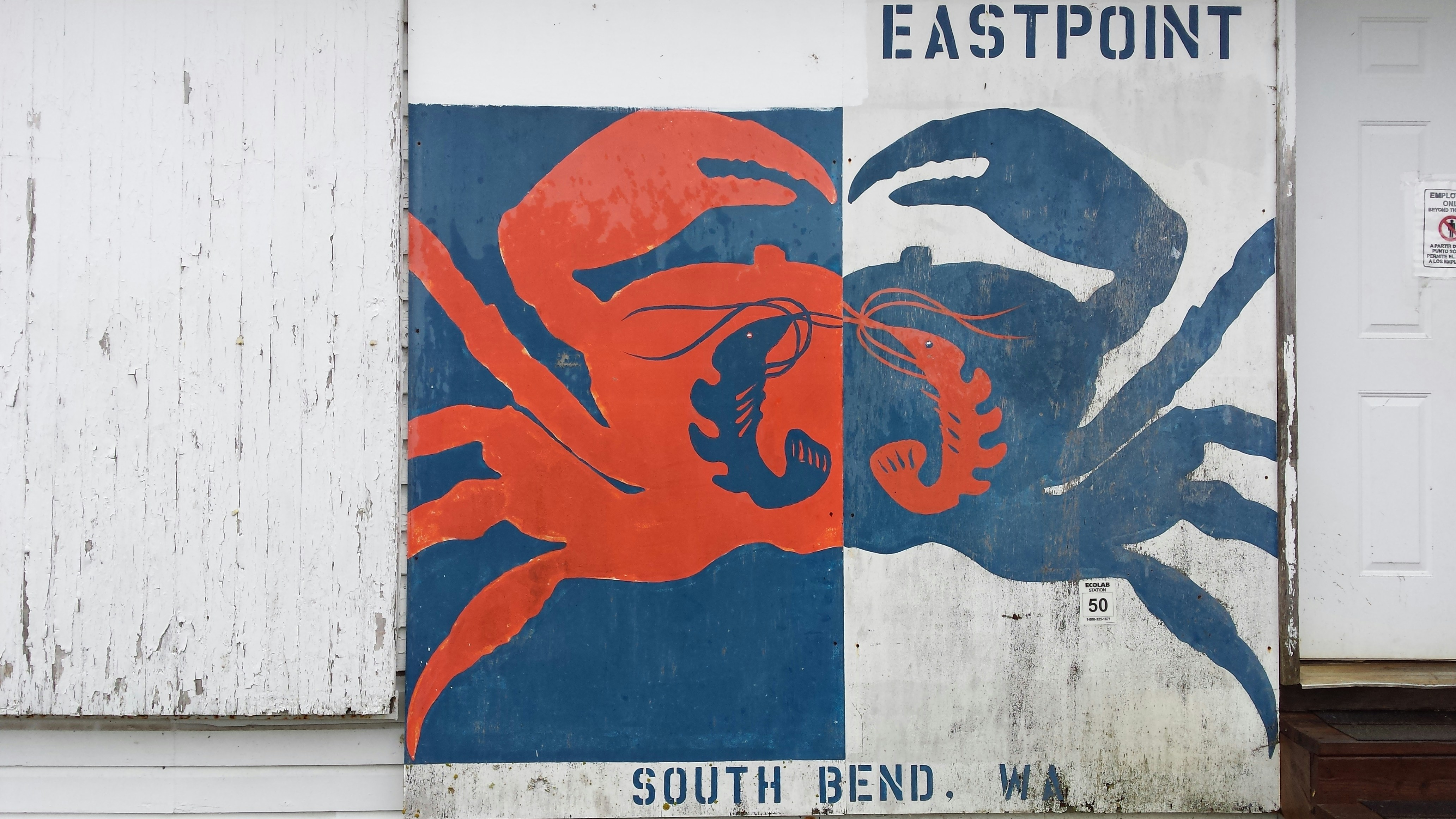 Mural of a red and blue crab on a weathered wall in South Bend, WA.