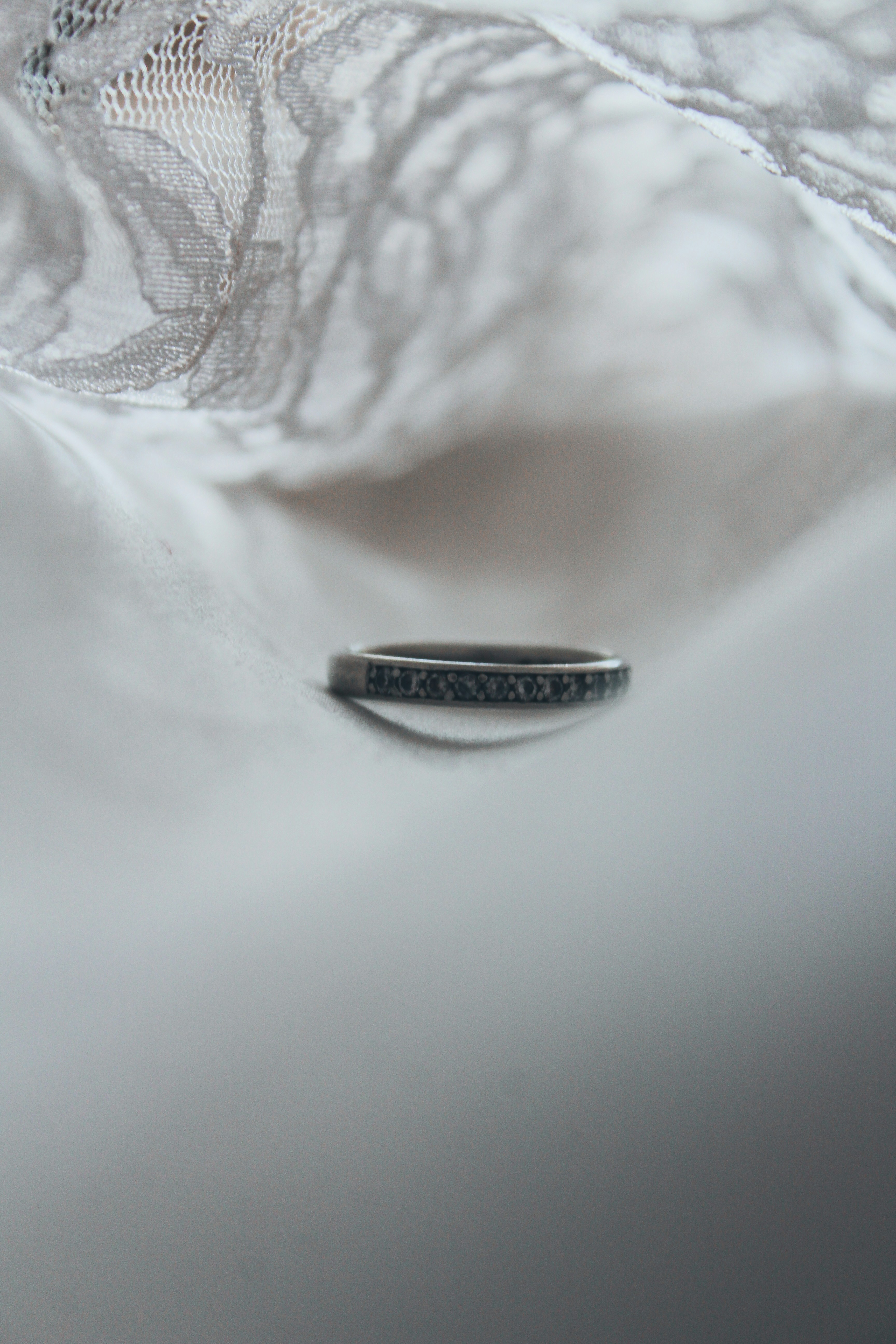 A delicate ring resting on soft lace fabric, showcasing intricate details and a subtle sparkle.