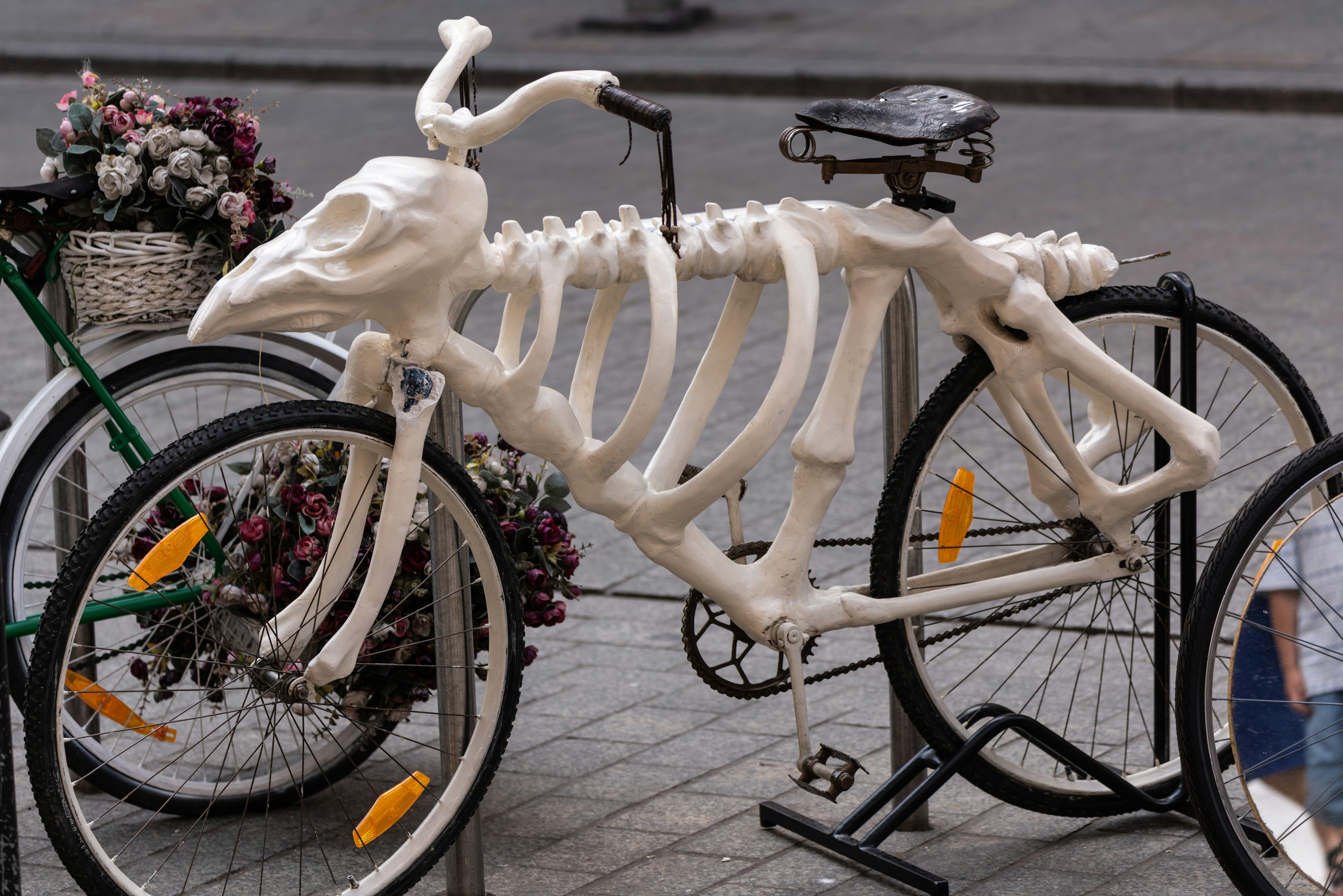 Skeleton on Wheels: A White Bicycle Sculpture Anchored by City Sidewalk