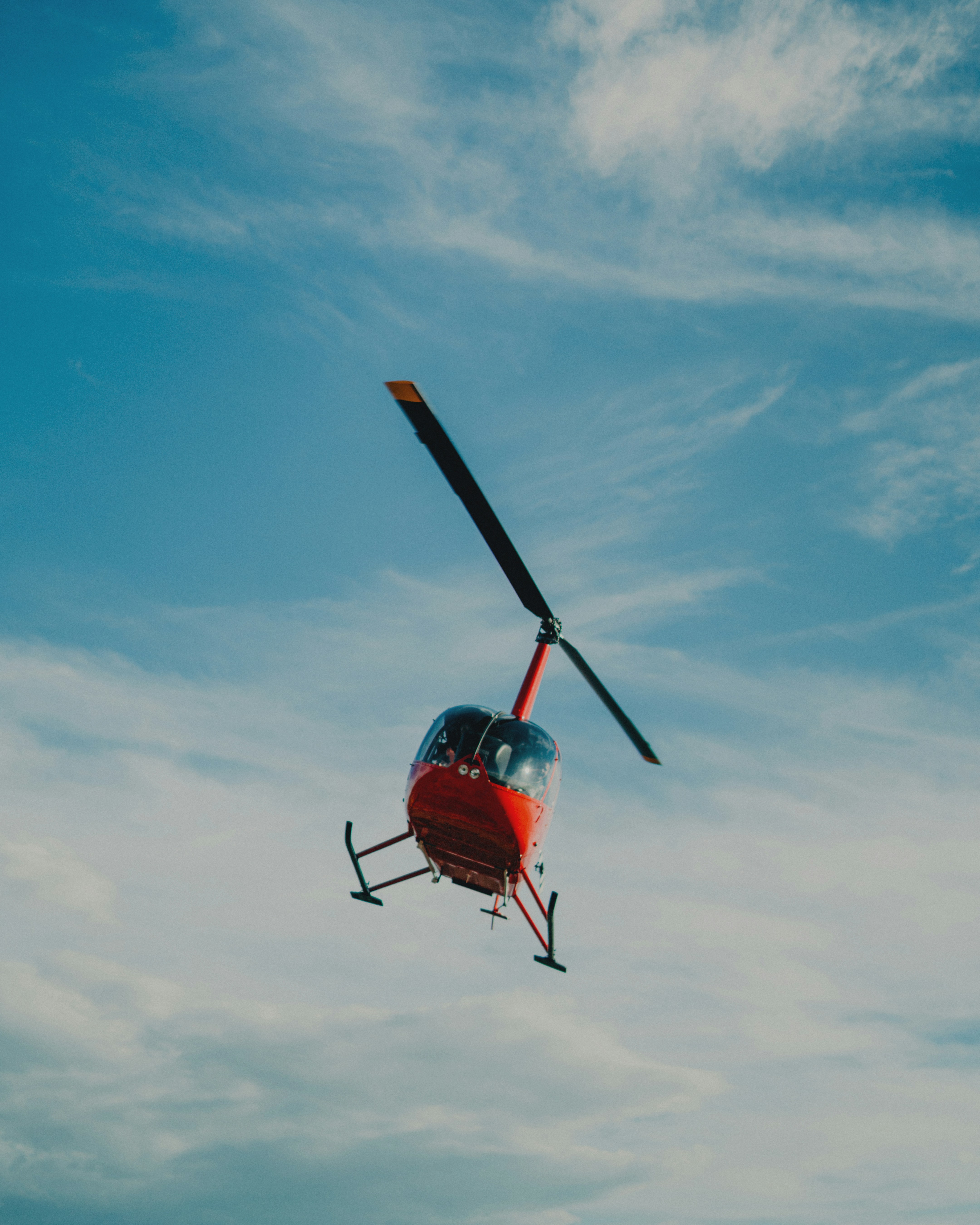 Red-Helix in the Blue: A helicopter climbs against a sapphire sky