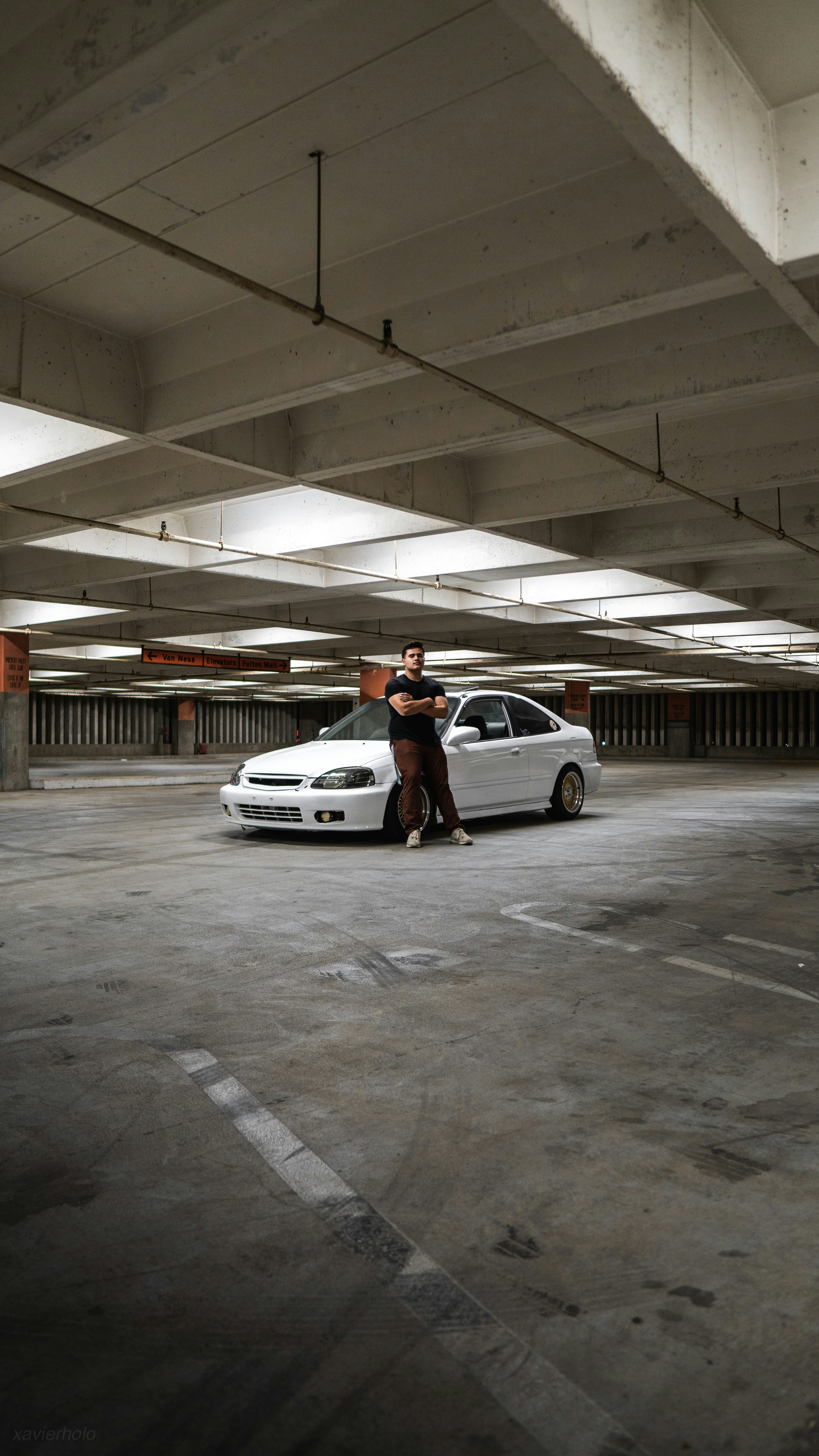 Garage Portrait: A Man with a White Sedan in a Quiet Parking Structure