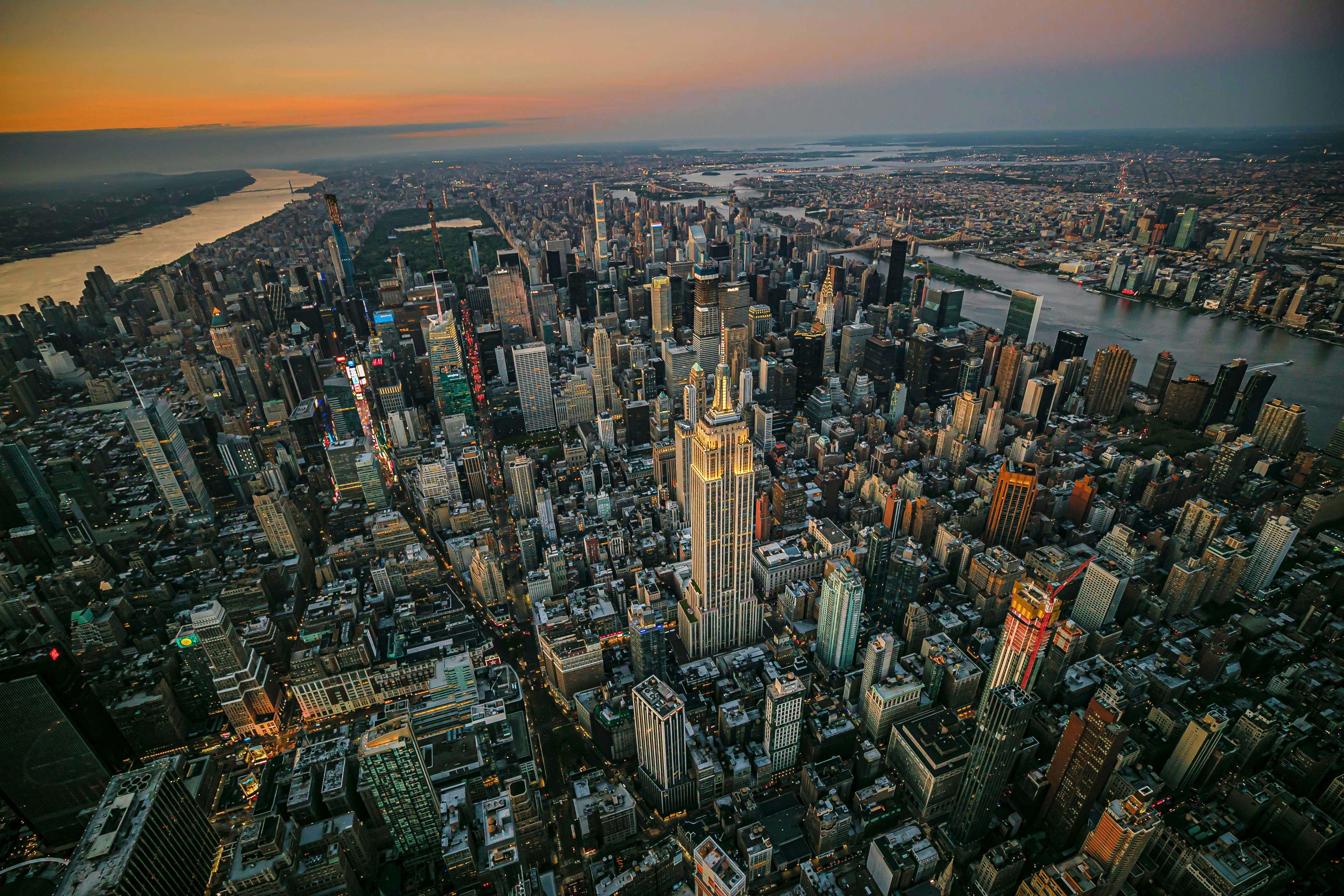 Aerial view of New York City showcasing the Empire State Building amidst a sprawling urban landscape at dusk.