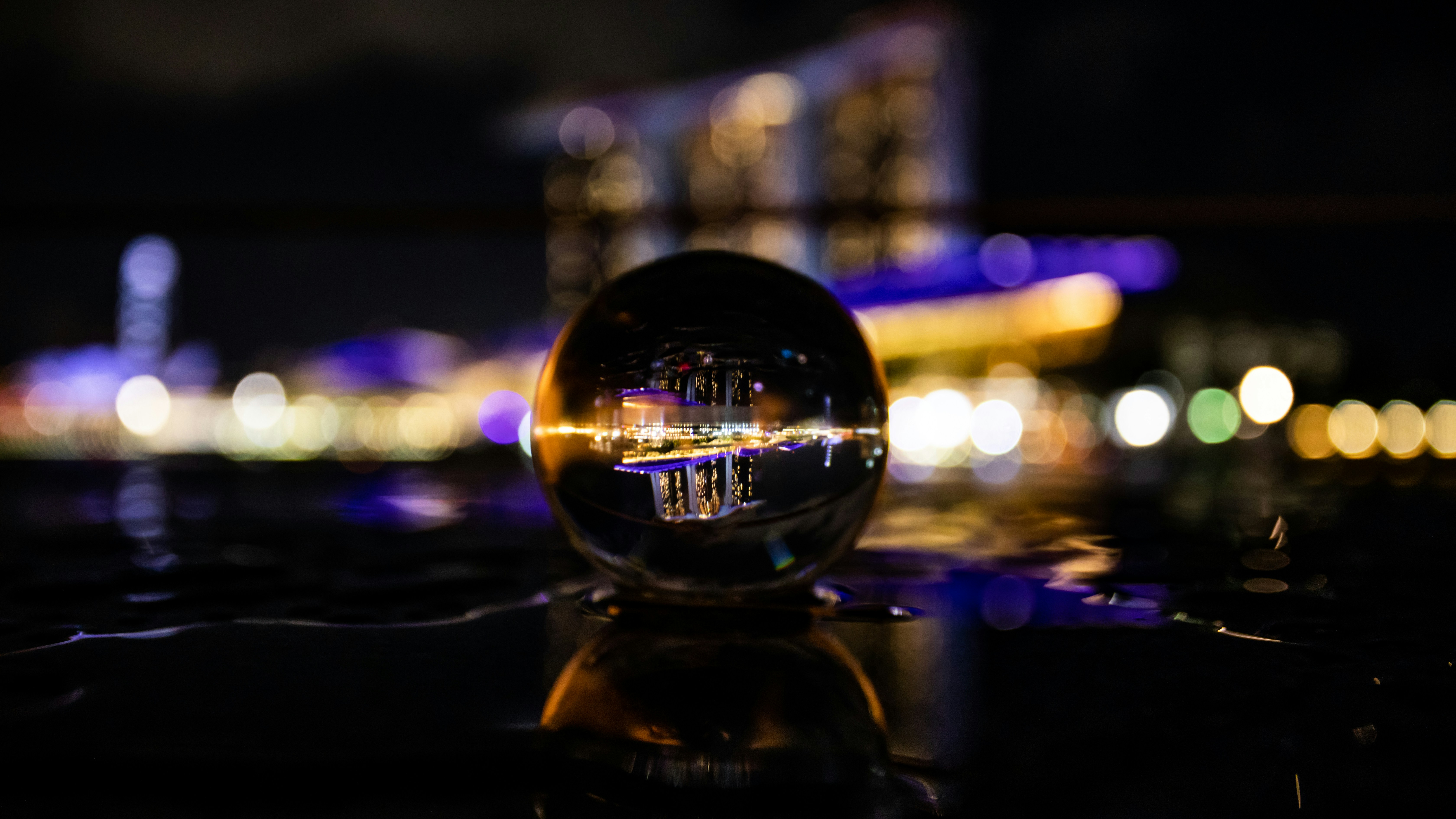 Crystal orb reflecting colorful city lights at night, creating a mesmerizing visual effect.