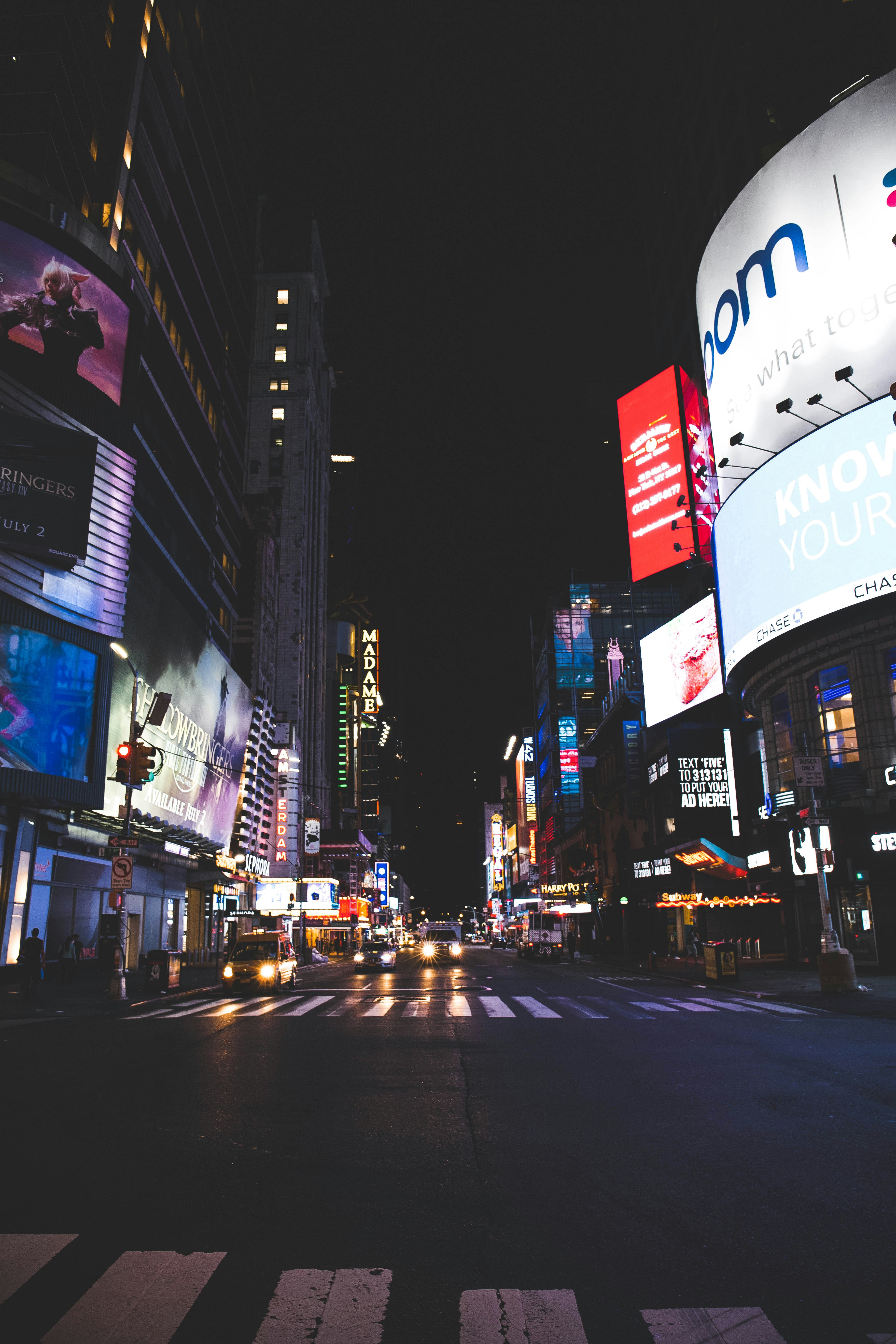 Illuminated billboards and vibrant lights of Times Square at night with a nearly empty street.