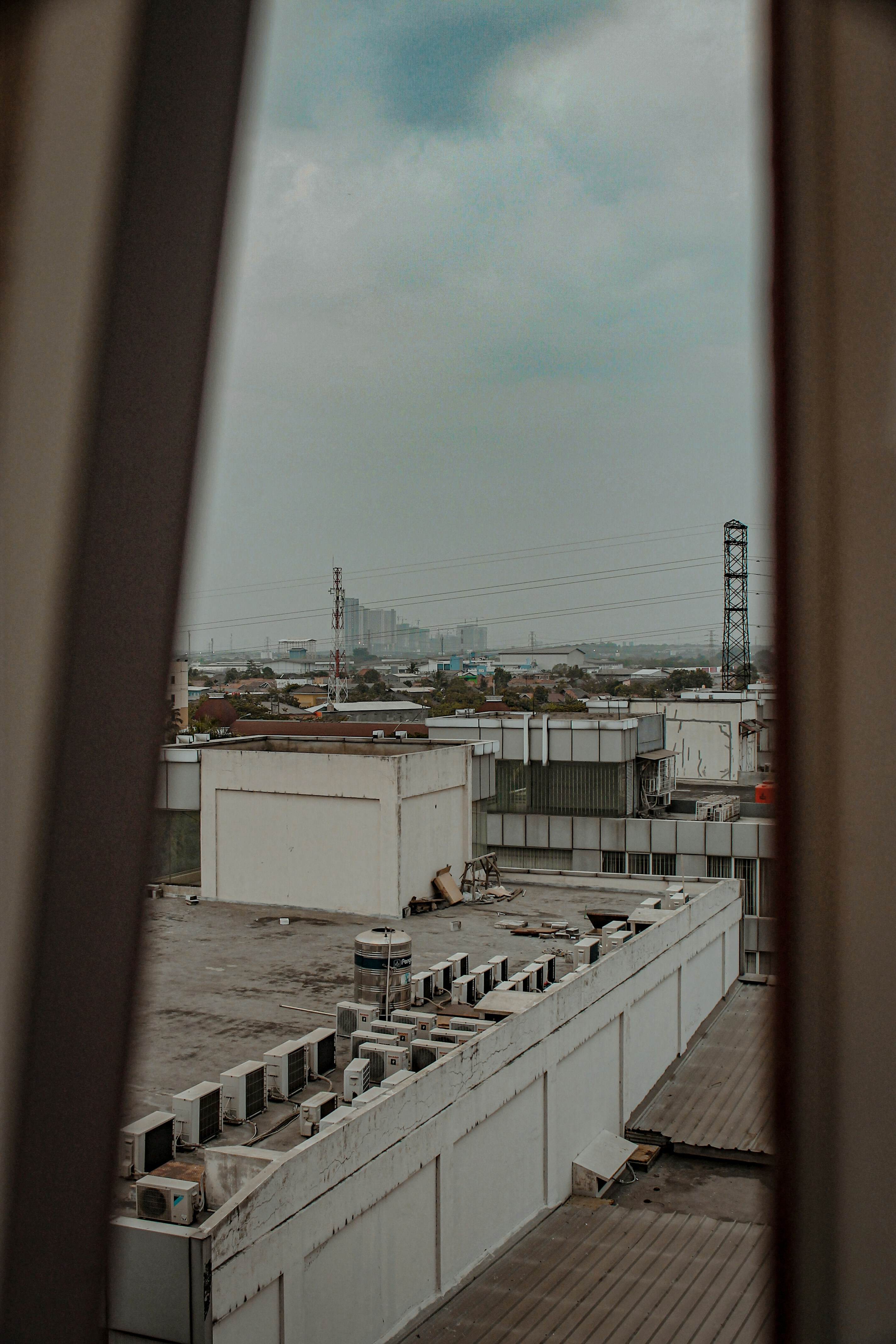 Through a Narrow Frame: Distant Skyline Over Rooftop Machinery
