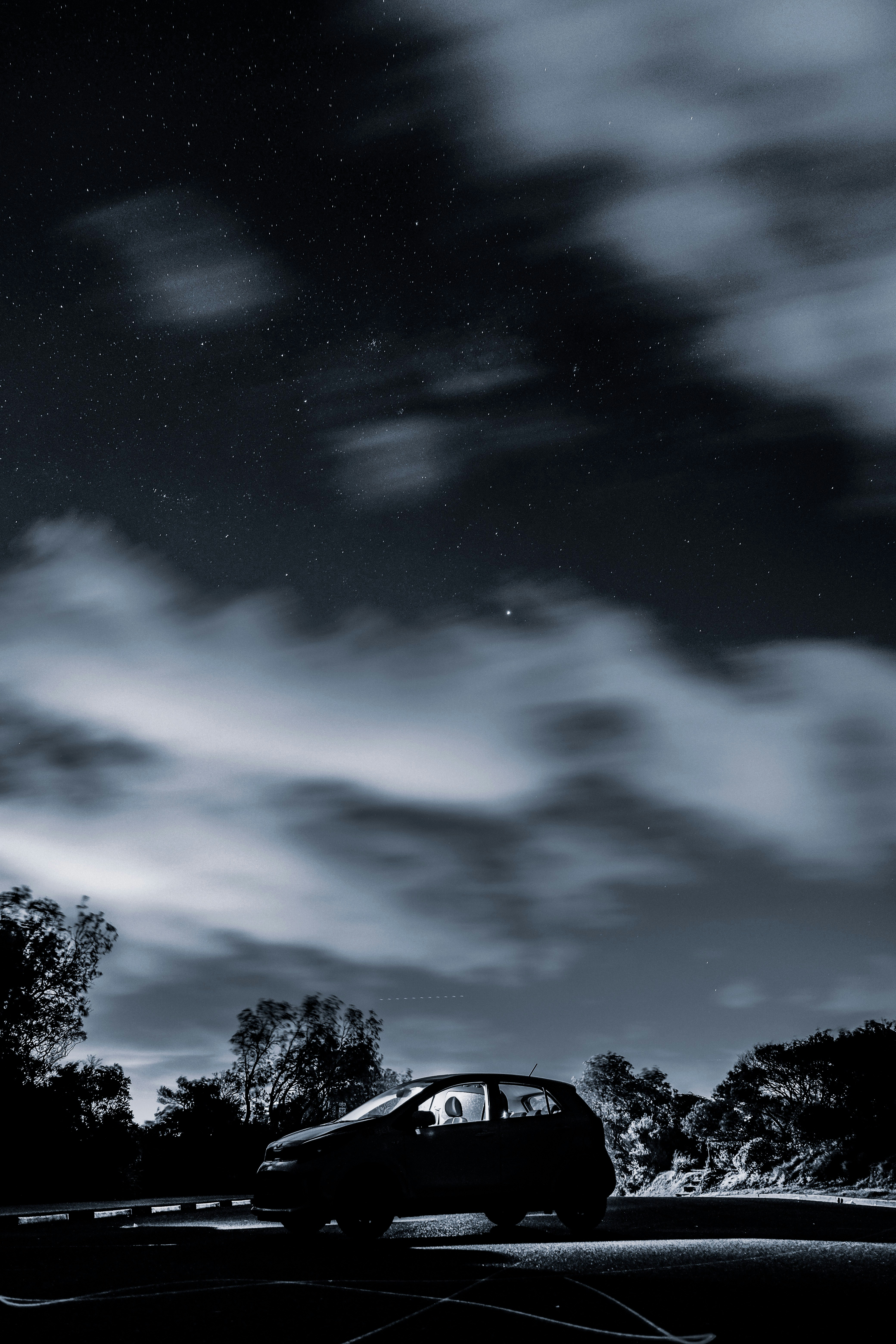 Midnight Roadside: A Lone Car Under a Star-Washed Sky