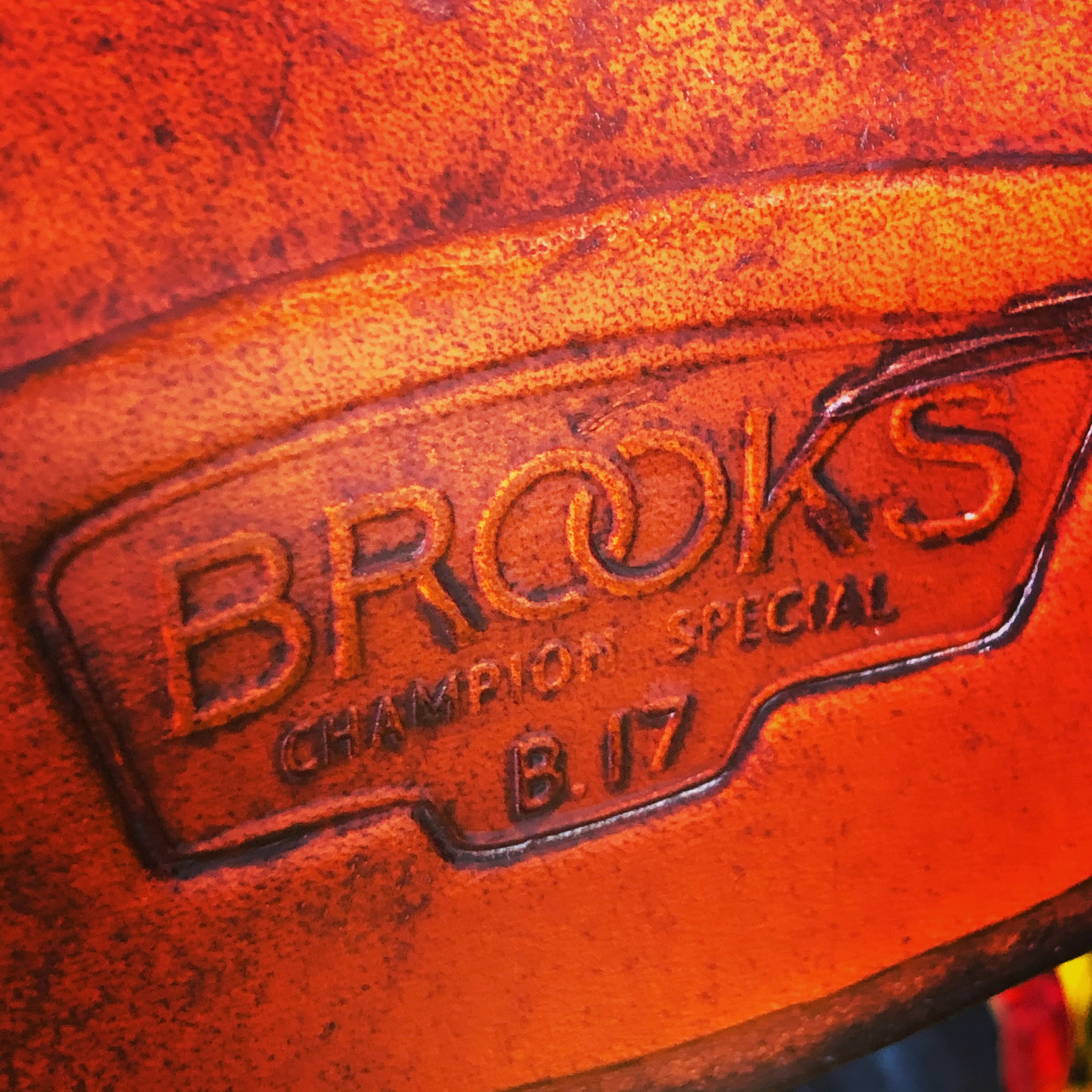 Close-up of a vintage Brooks B17 saddle showcasing intricate details and rich patina. The craftsmanship highlights the saddle's legacy in cycling history.
