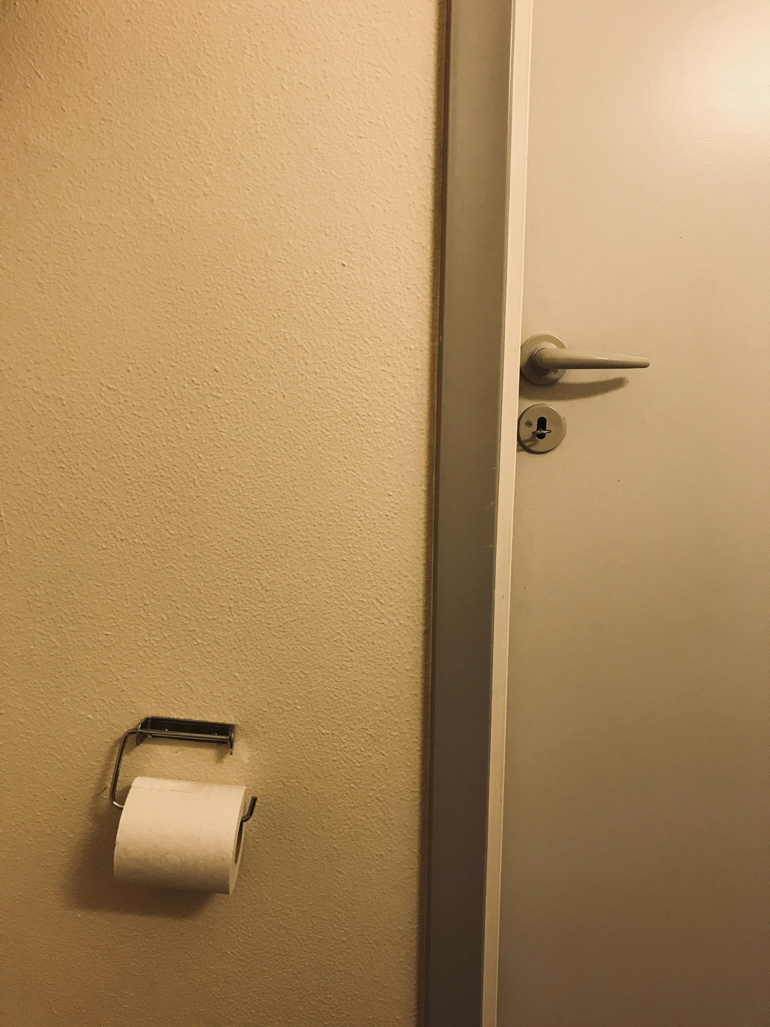 Amber Threshold: A Minimal Bathroom Corner with a Paper Roll