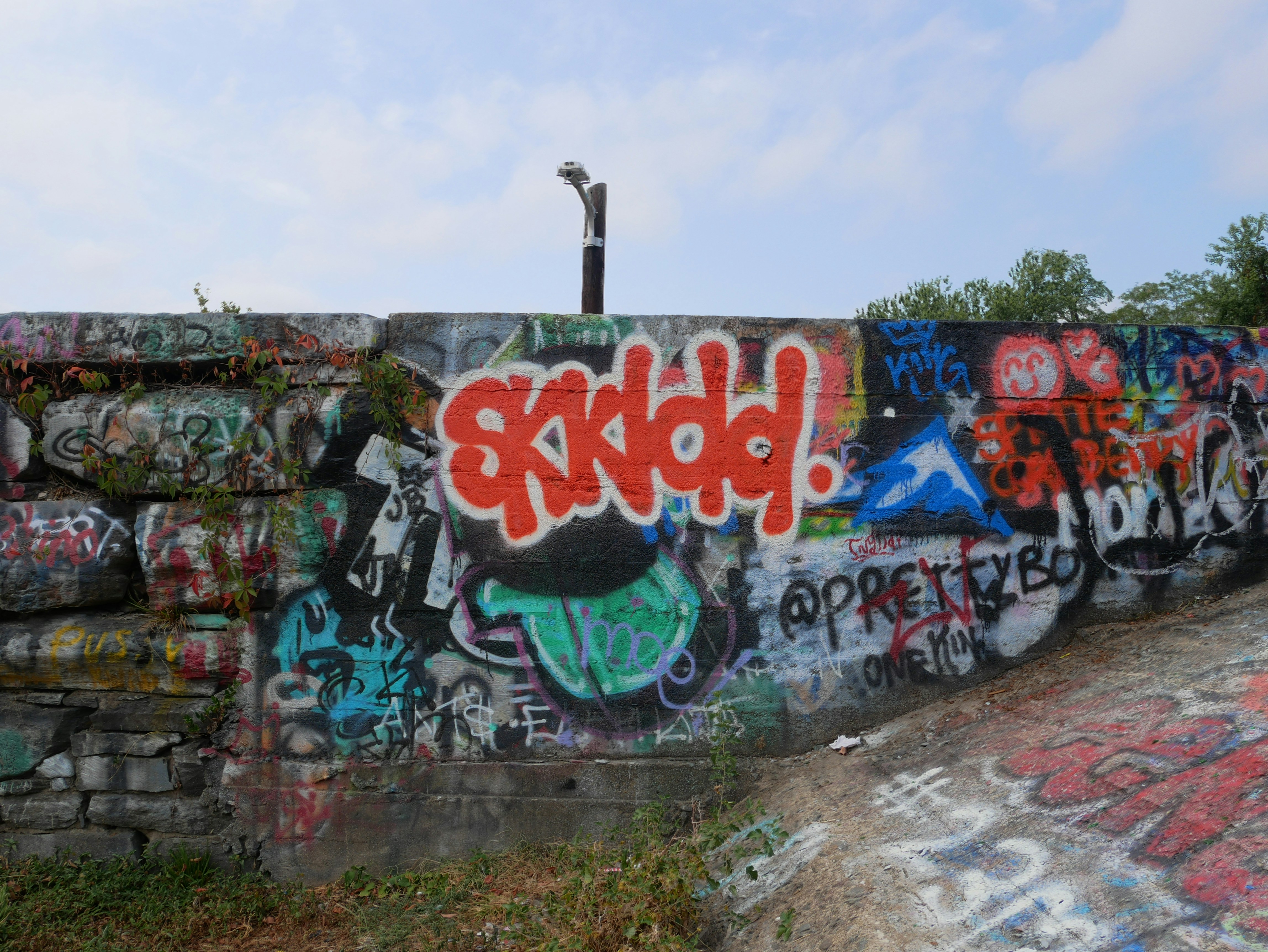 Crimson Script on a Graffiti-Wrapped Wall, Framed by a Weathered Ramp