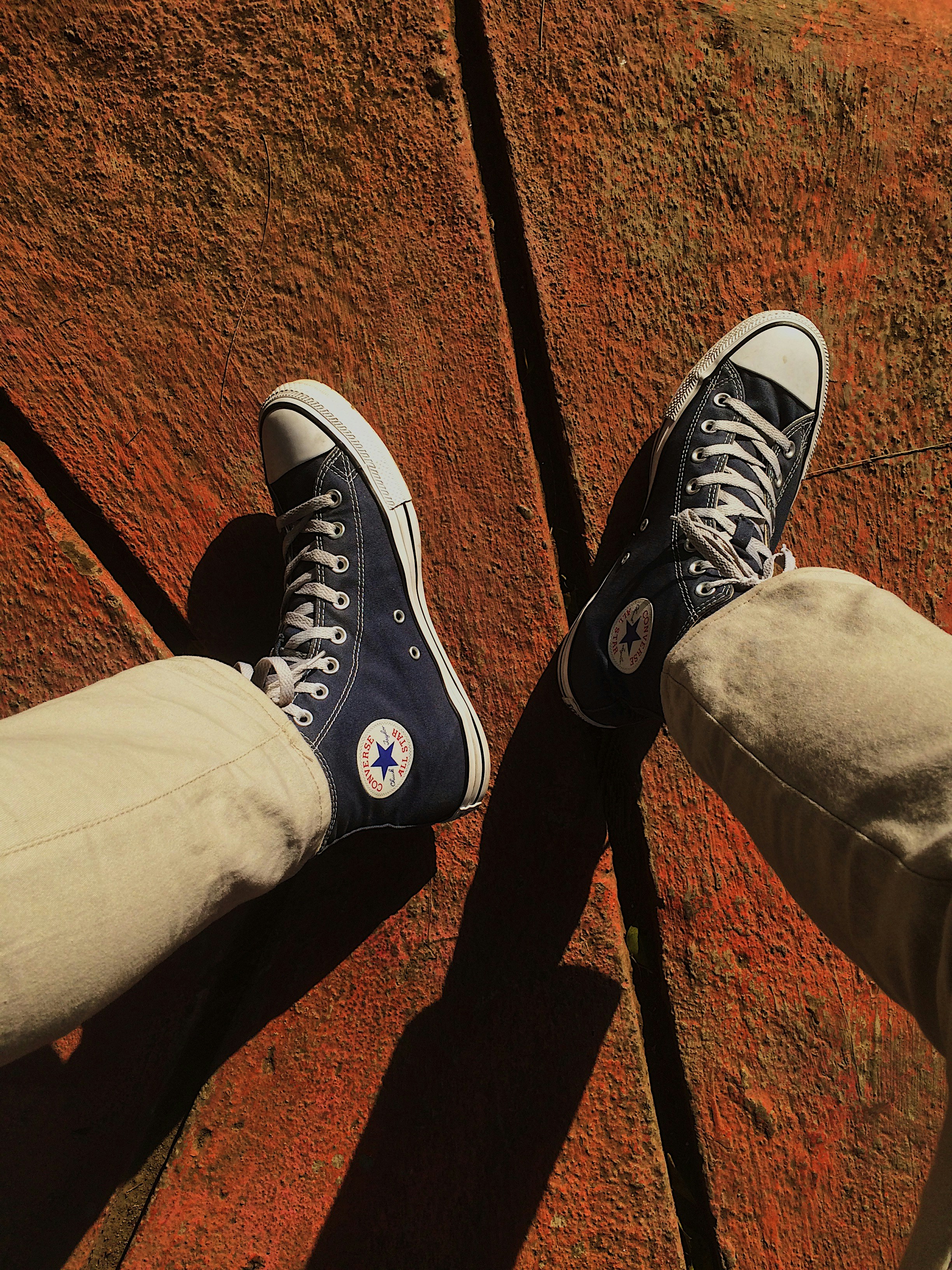 Ground-Level Echo: Navy Converse on Rust-Red Planks