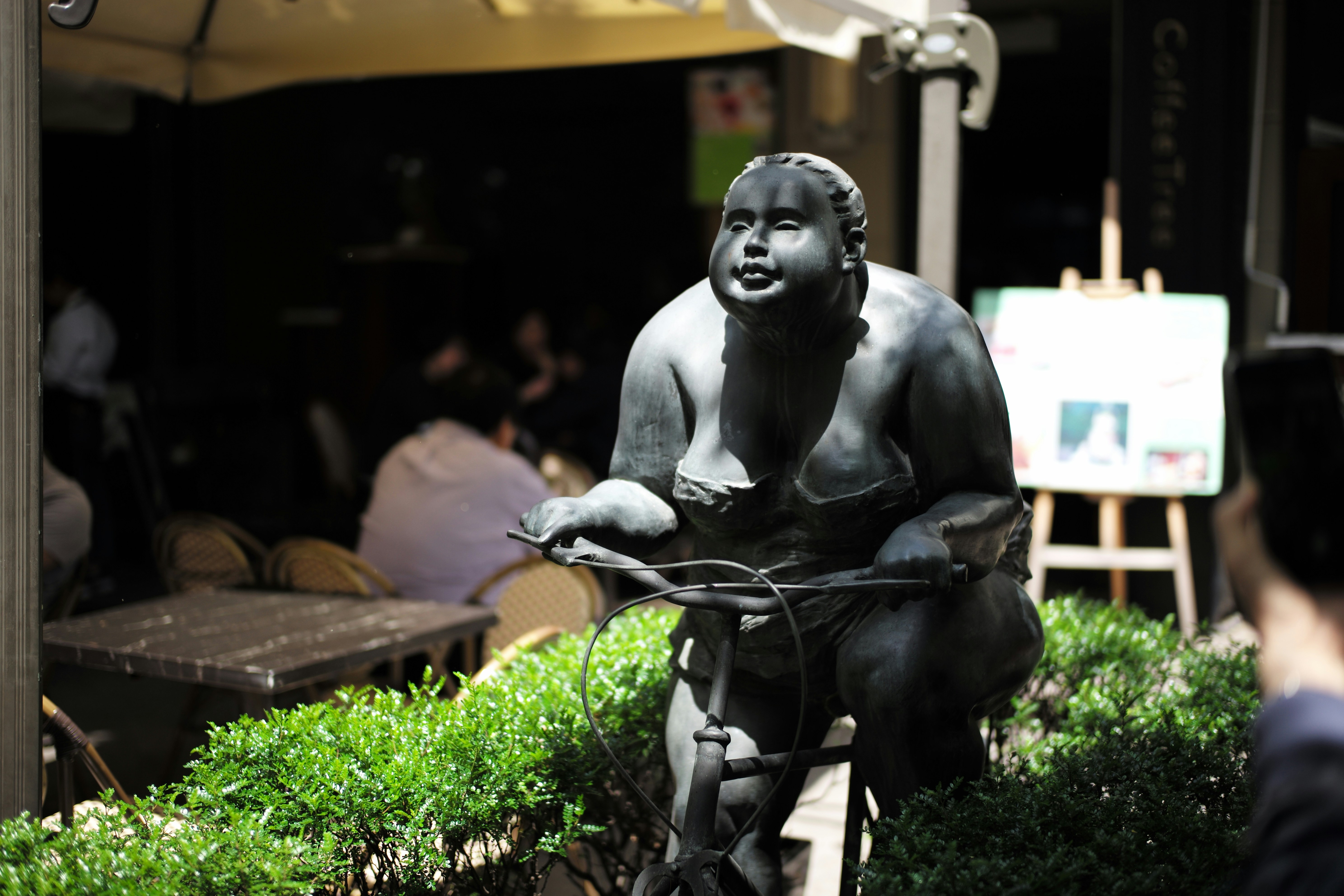 Bronze cyclist at the café gate