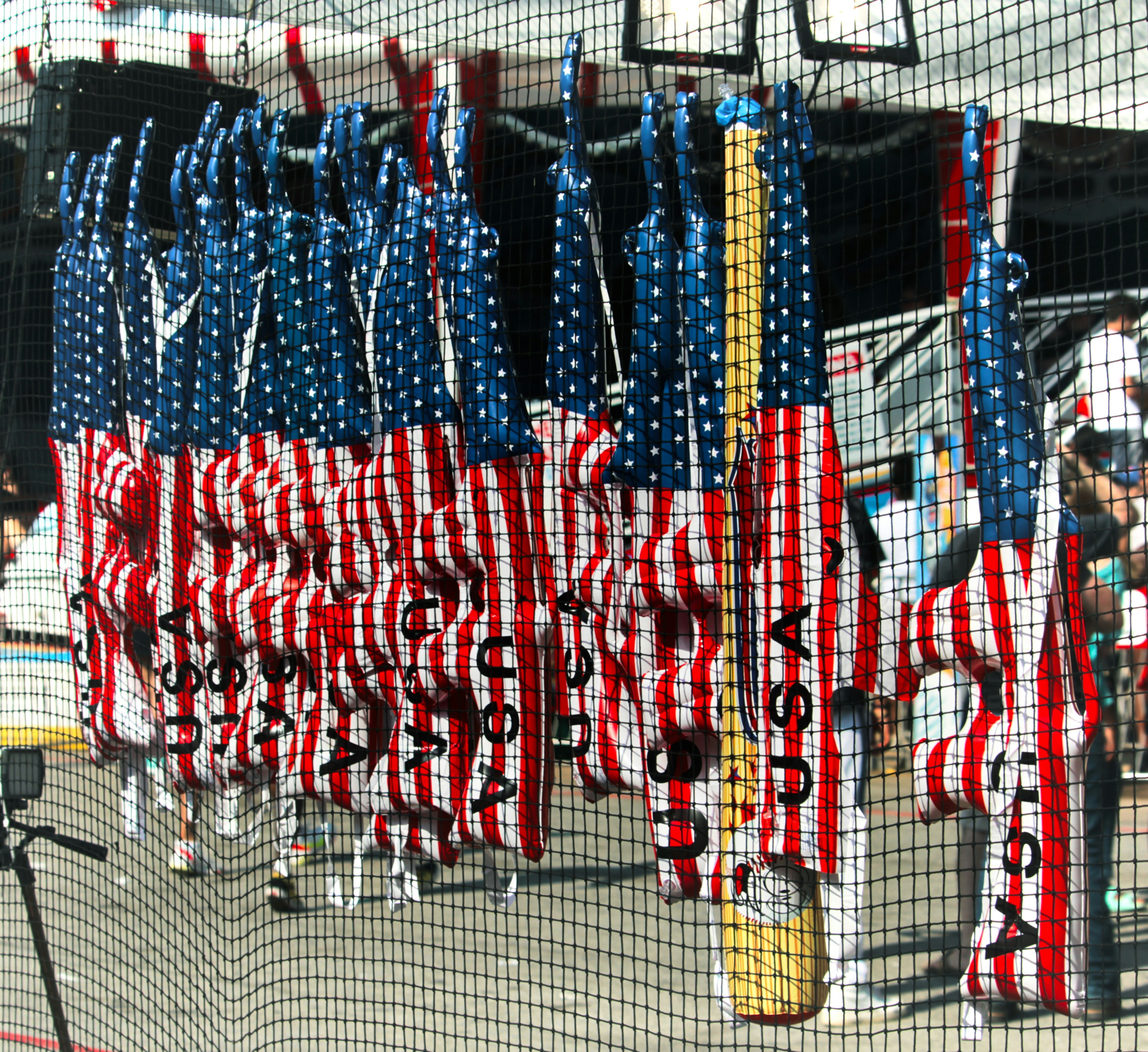 A series of rifles draped in the American flag, symbolizing patriotism and national pride, hang against a backdrop of spectators. 