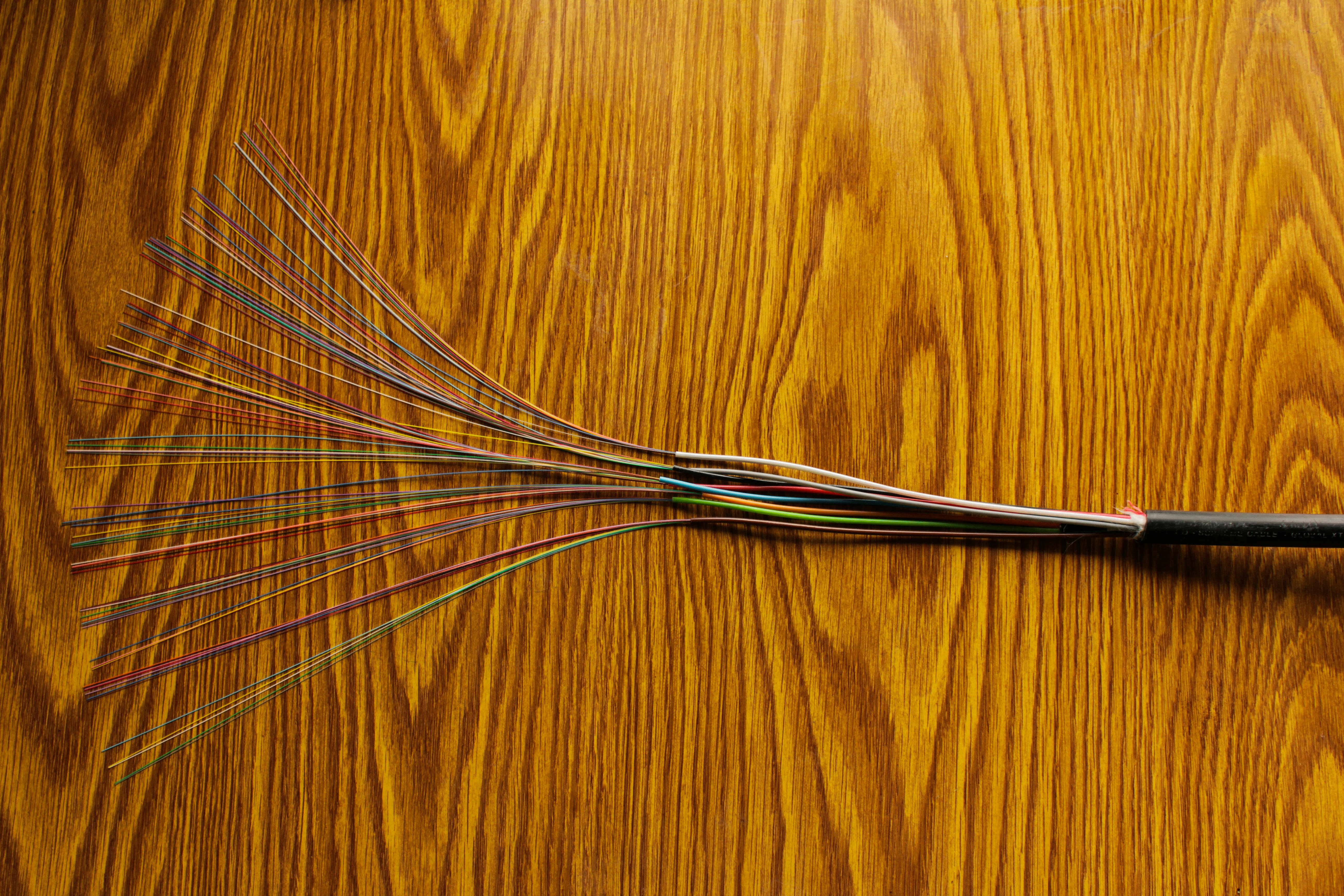 Colorful Ribbon Wires Fanned Across a Warm Wood Surface