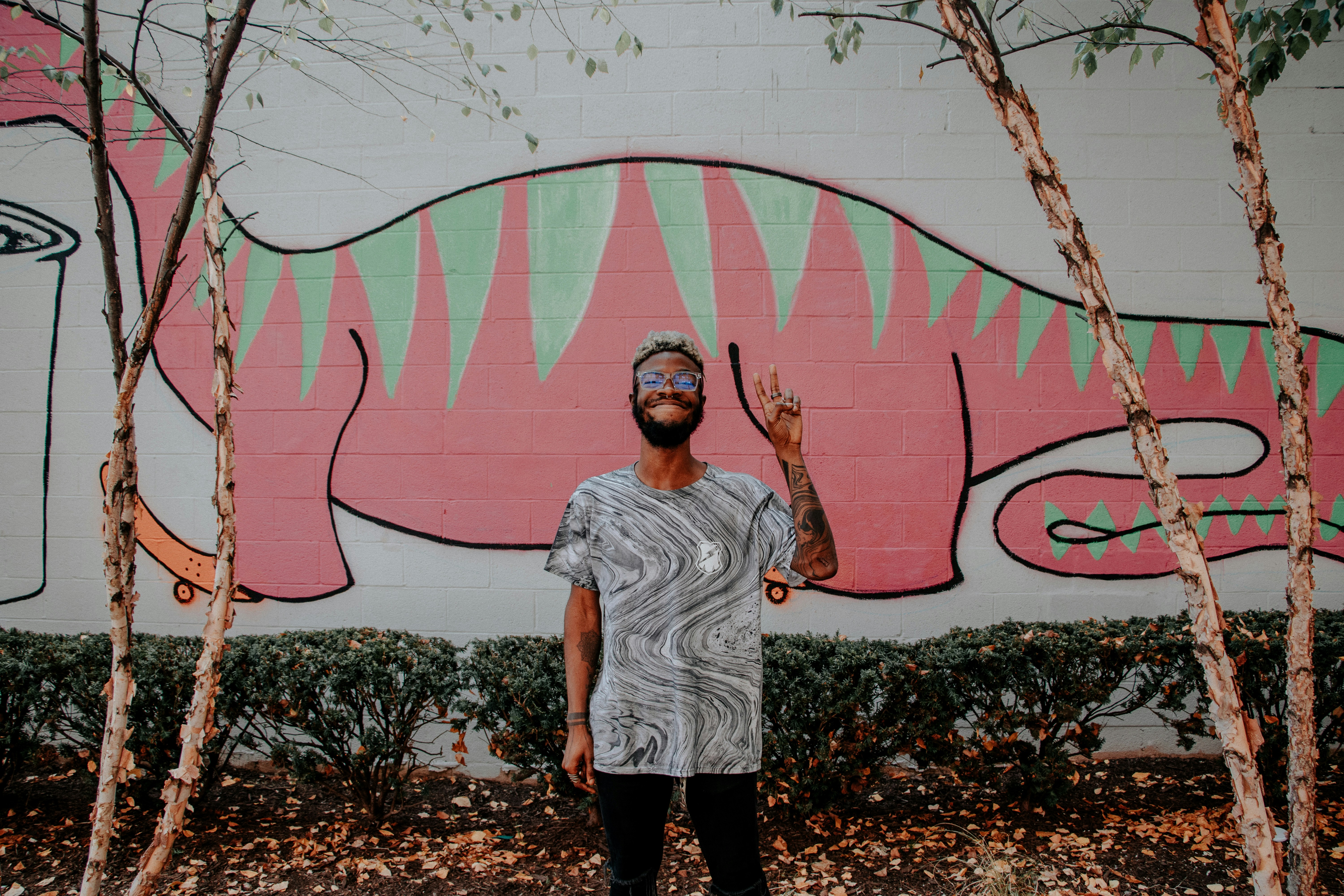 Center Stage Before a Pink Dinosaur Graffiti: A Man in a Swirl-Pattern Tee