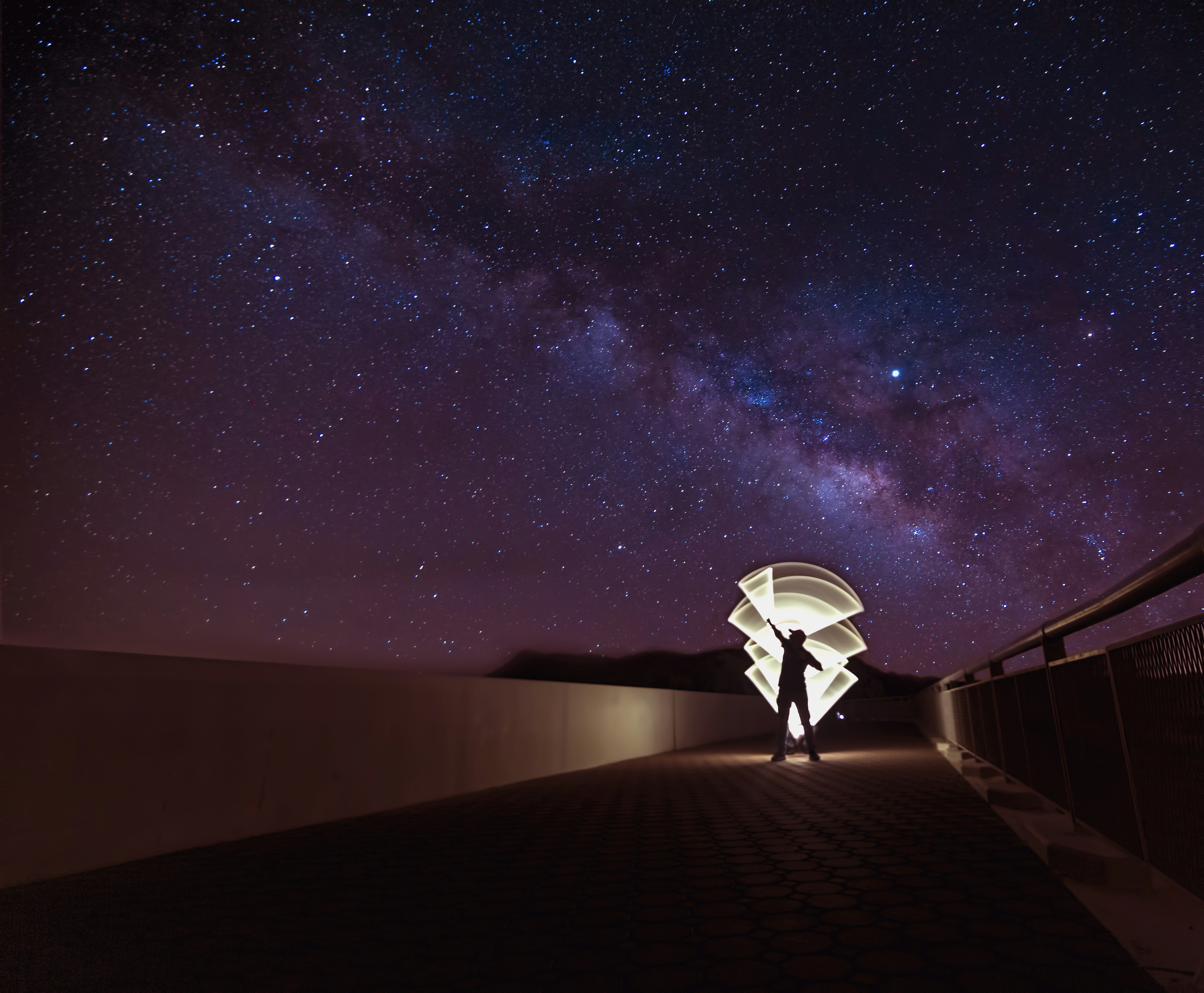 Man on top of the building waves light torch under starry night photo ...