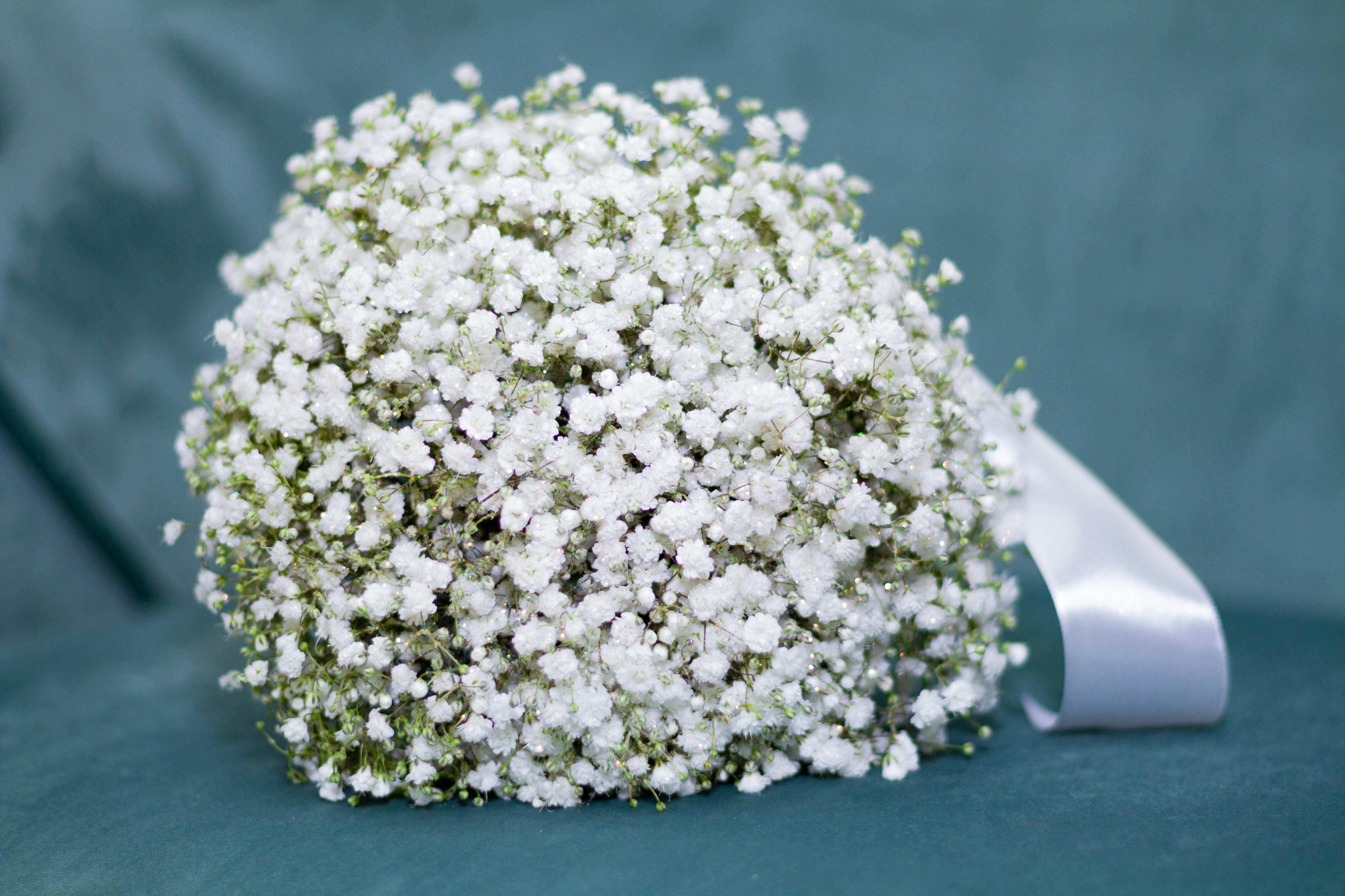 Delicate bouquet of gypsophila with a satin ribbon, resting on a soft teal surface.