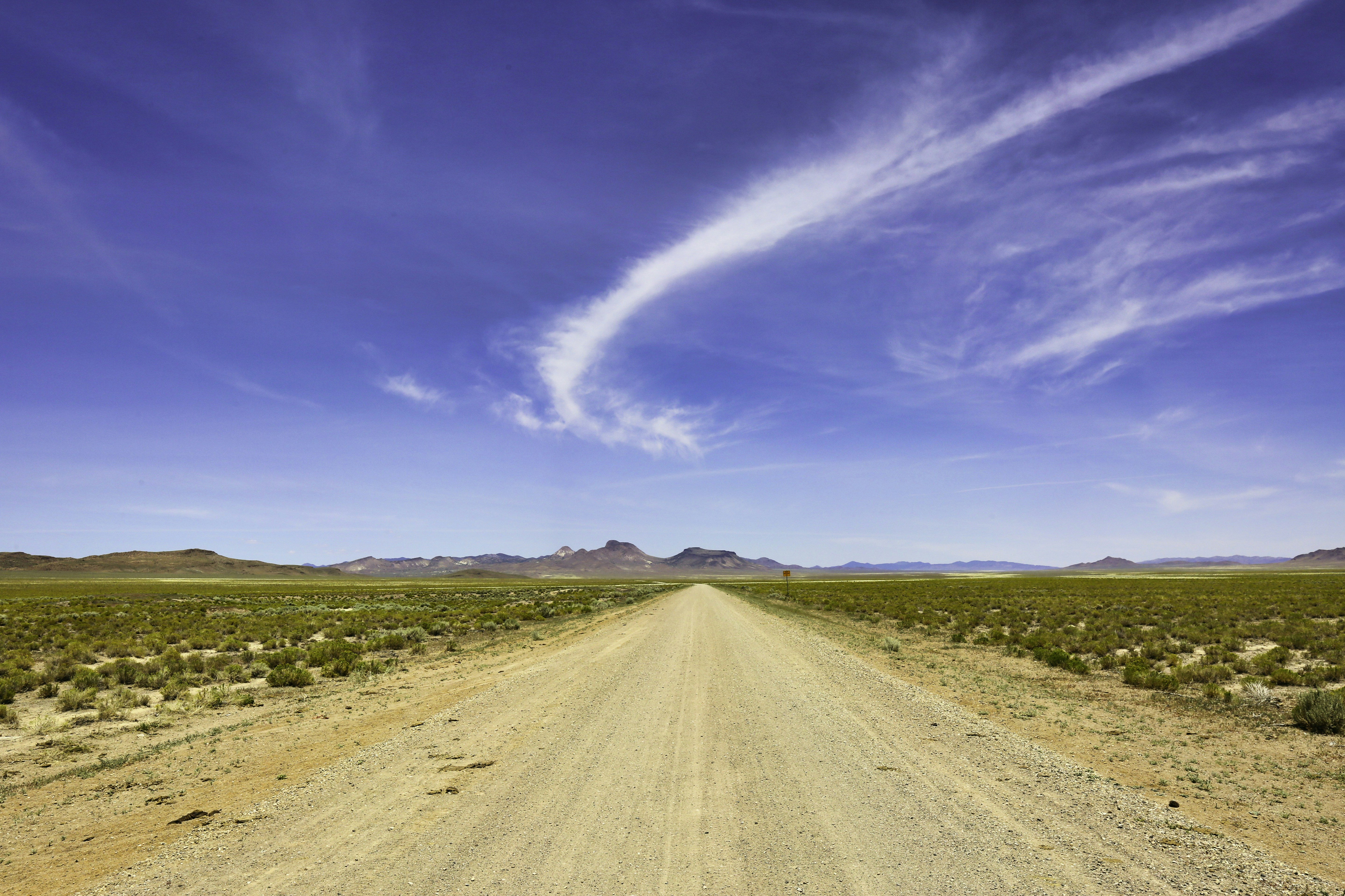 Open spaces dirt road in the middle of Nevada with a curious curved cloud in the sky. I used to hate Nevada, but on this day...this day, it wasn't so bad. | rocky road photography