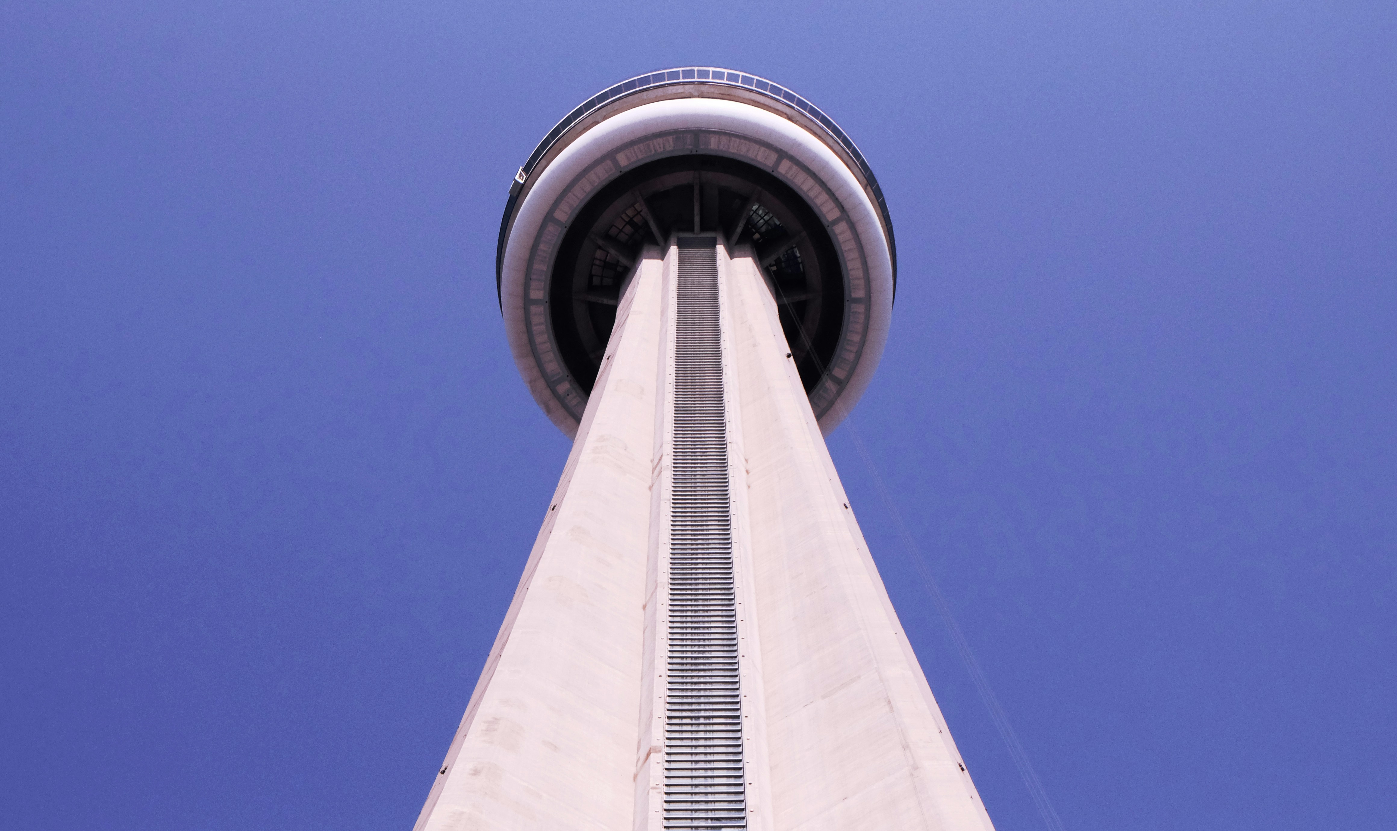 The CN Tower rises majestically against a clear blue sky, showcasing its sleek design and architectural grandeur.