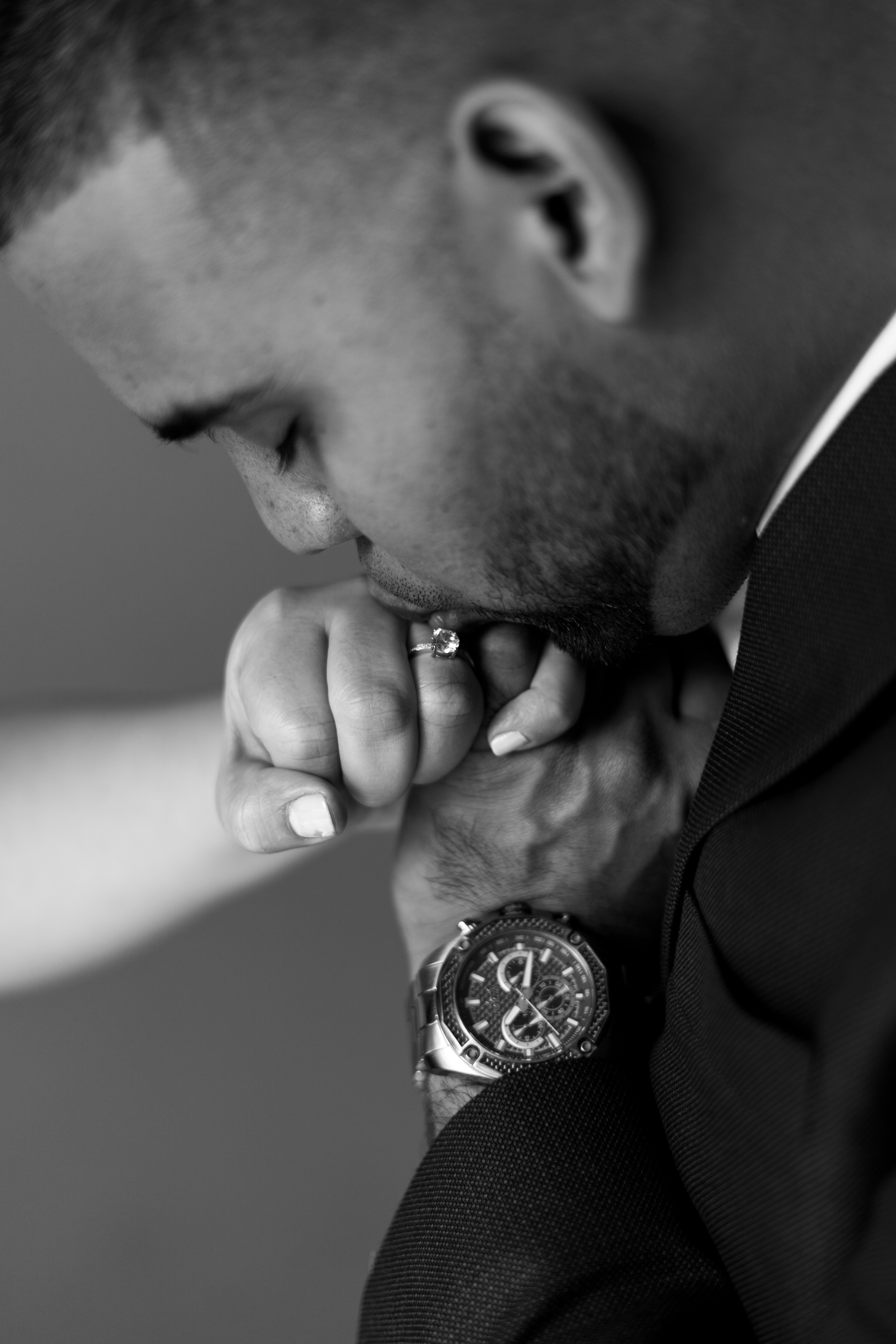 A man gently kissing a woman's hand, showcasing a moment of tenderness and intimacy. The focus is on the watch and the engagement ring, symbolizing commitment.