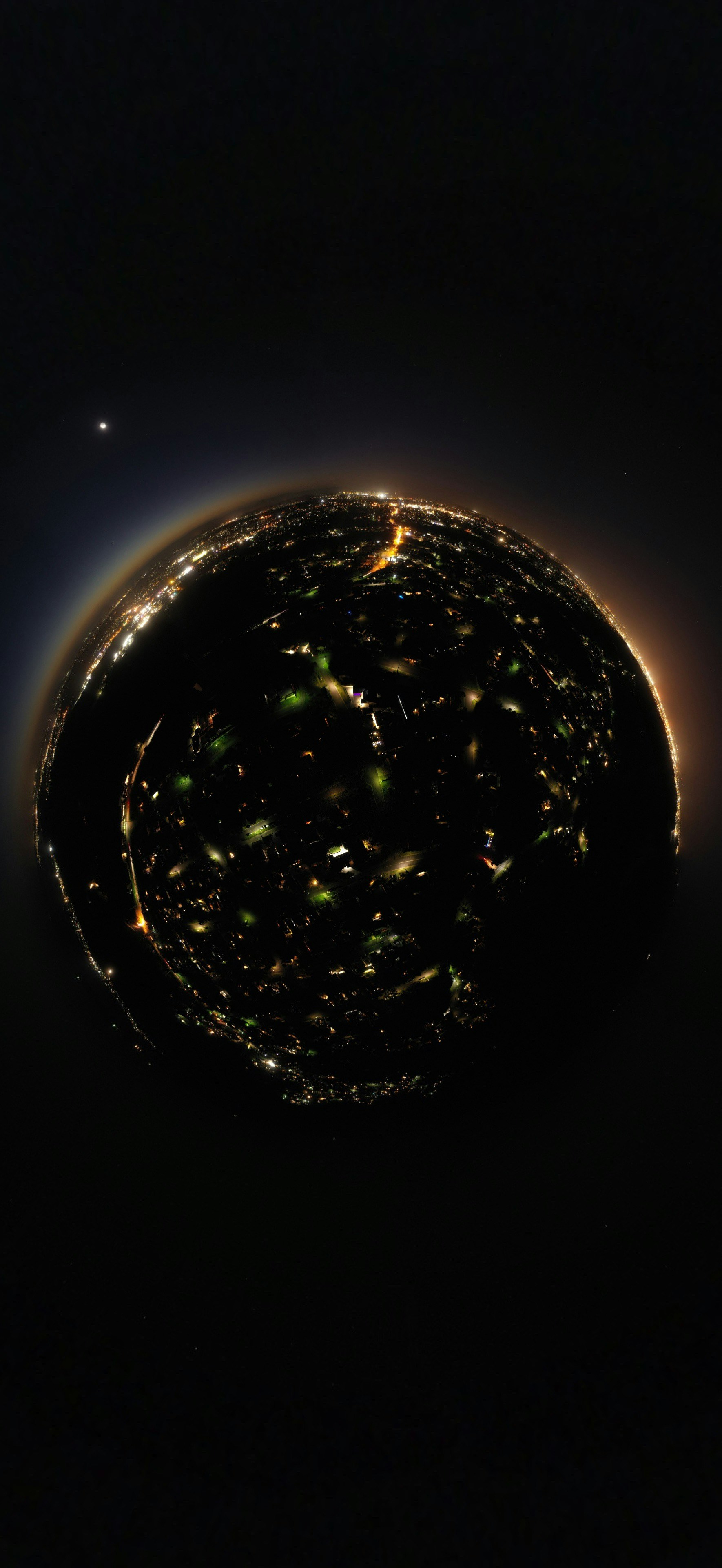 A panoramic view of a city illuminated at night, showcasing vibrant lights and the curvature of the horizon. The scene captures the essence of urban life against a starlit sky.