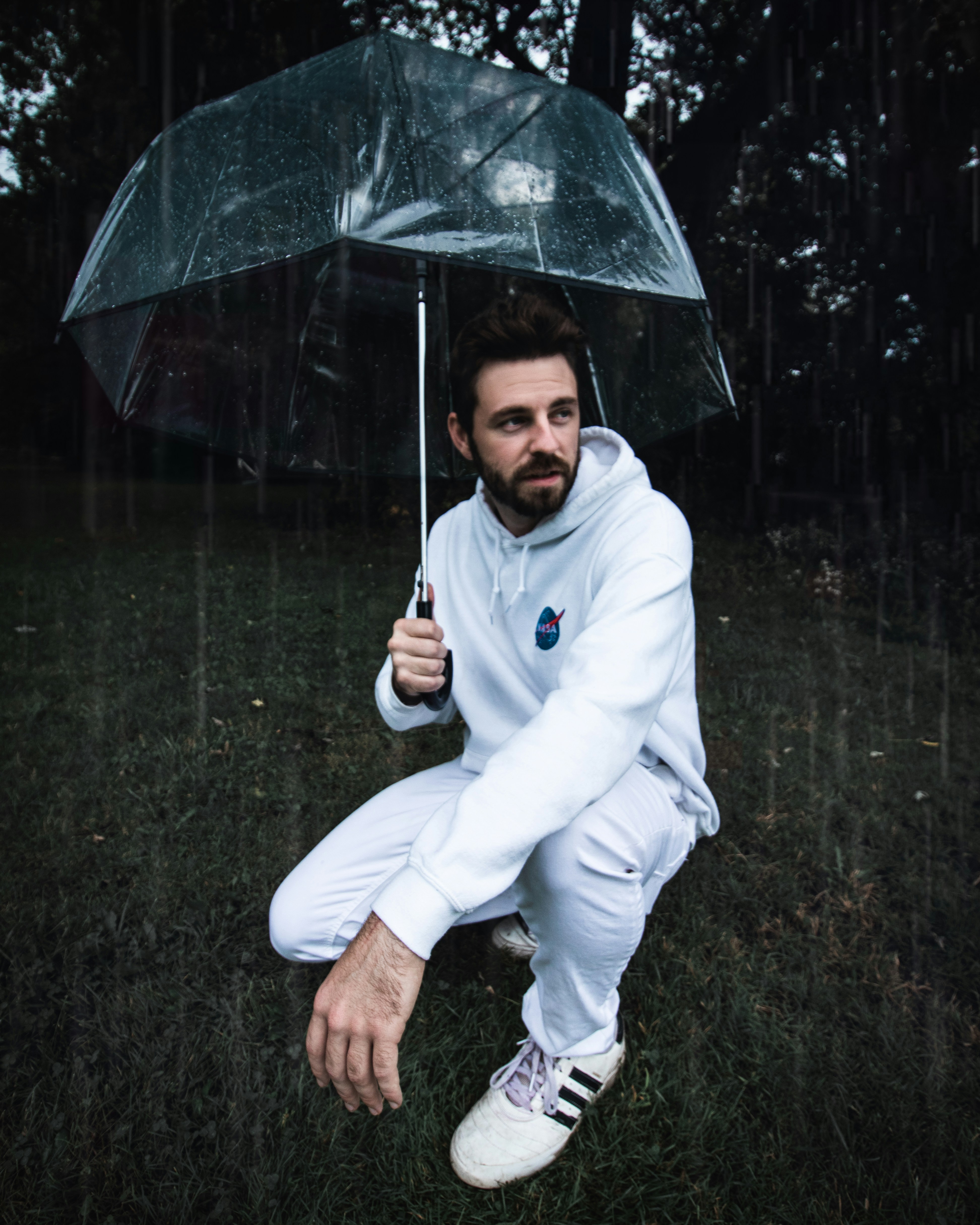Clear Umbrella, Quiet Gaze: A Rainy Park Portrait in White Hoodie
