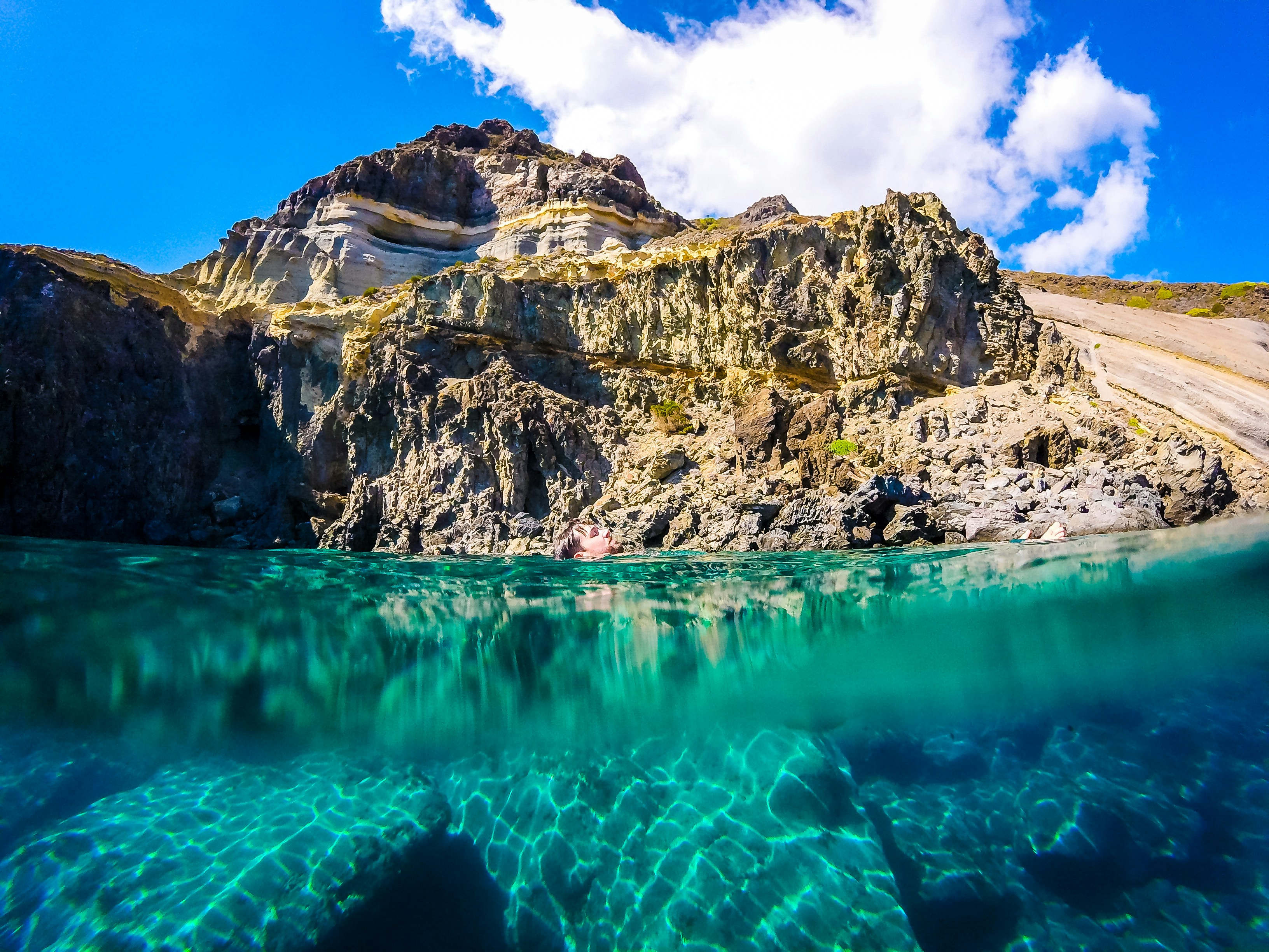 Vibrant turquoise water meets dramatic rocky cliffs under a bright blue sky, showcasing the beauty of nature's contrasts.