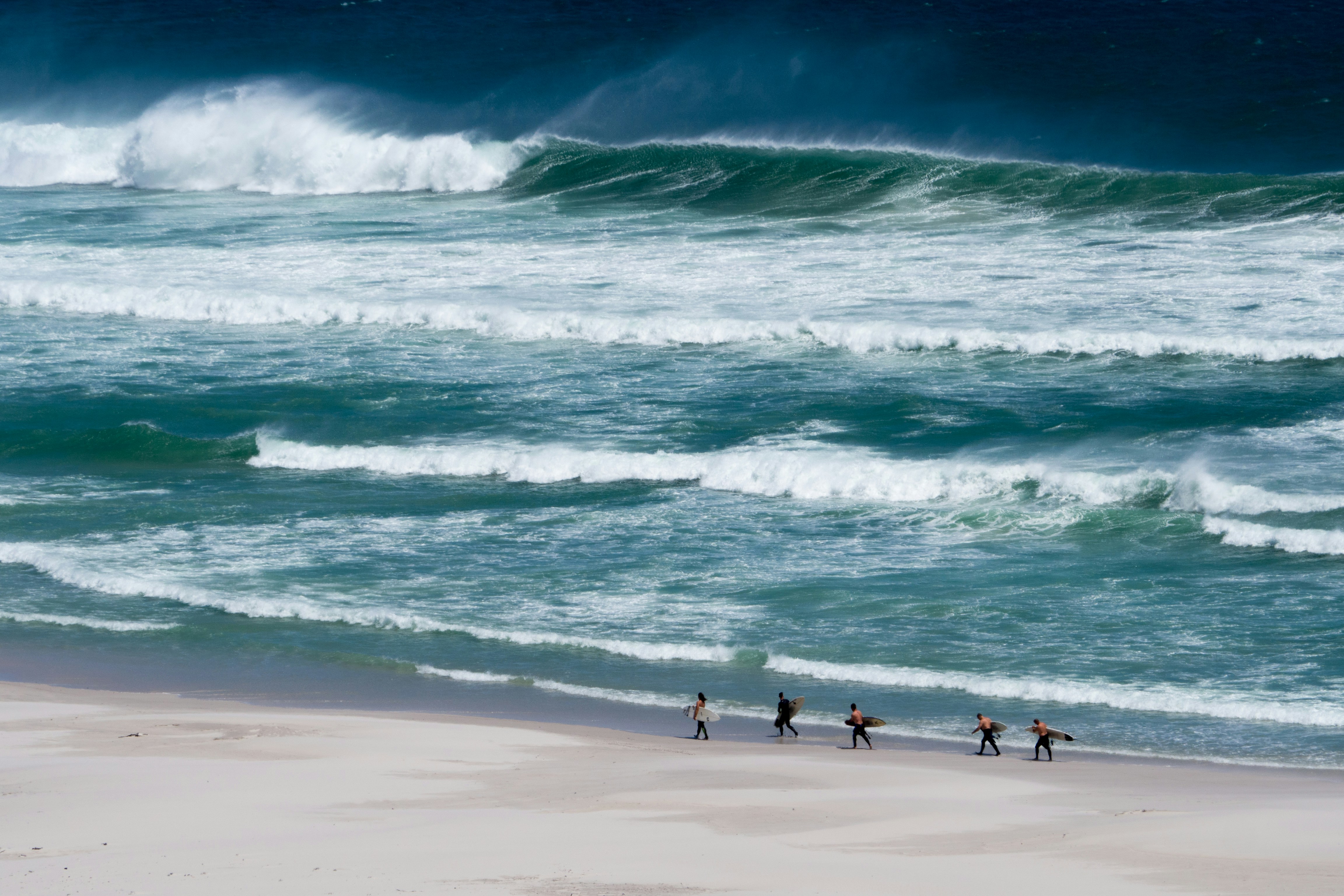 Shoreline Cadence: Five Figures Trek the Turquoise Tide Along a Sunlit Beach