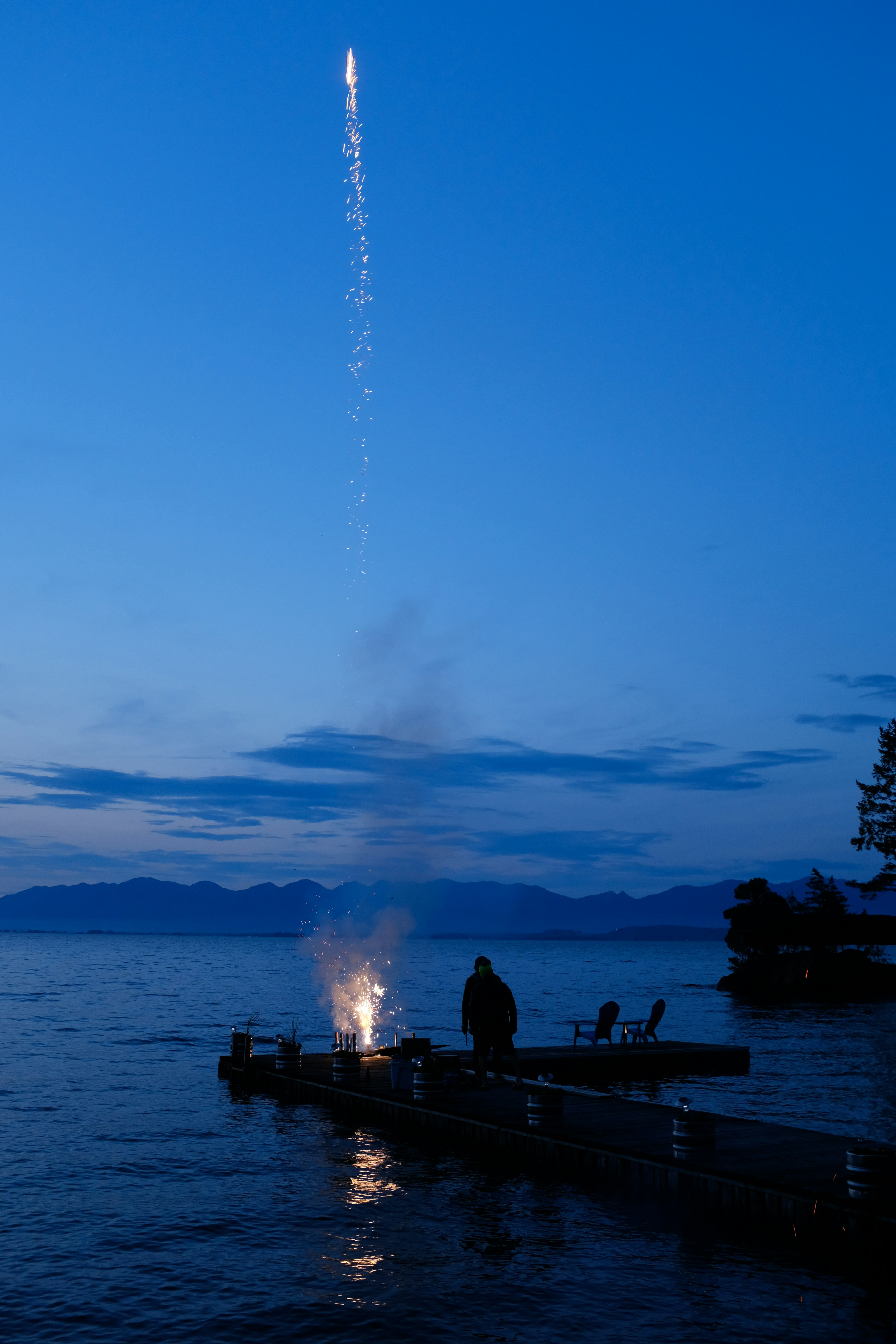 Blue Hour Spark: A Quiet Lake Pier Witnesses a Vertical Firework
