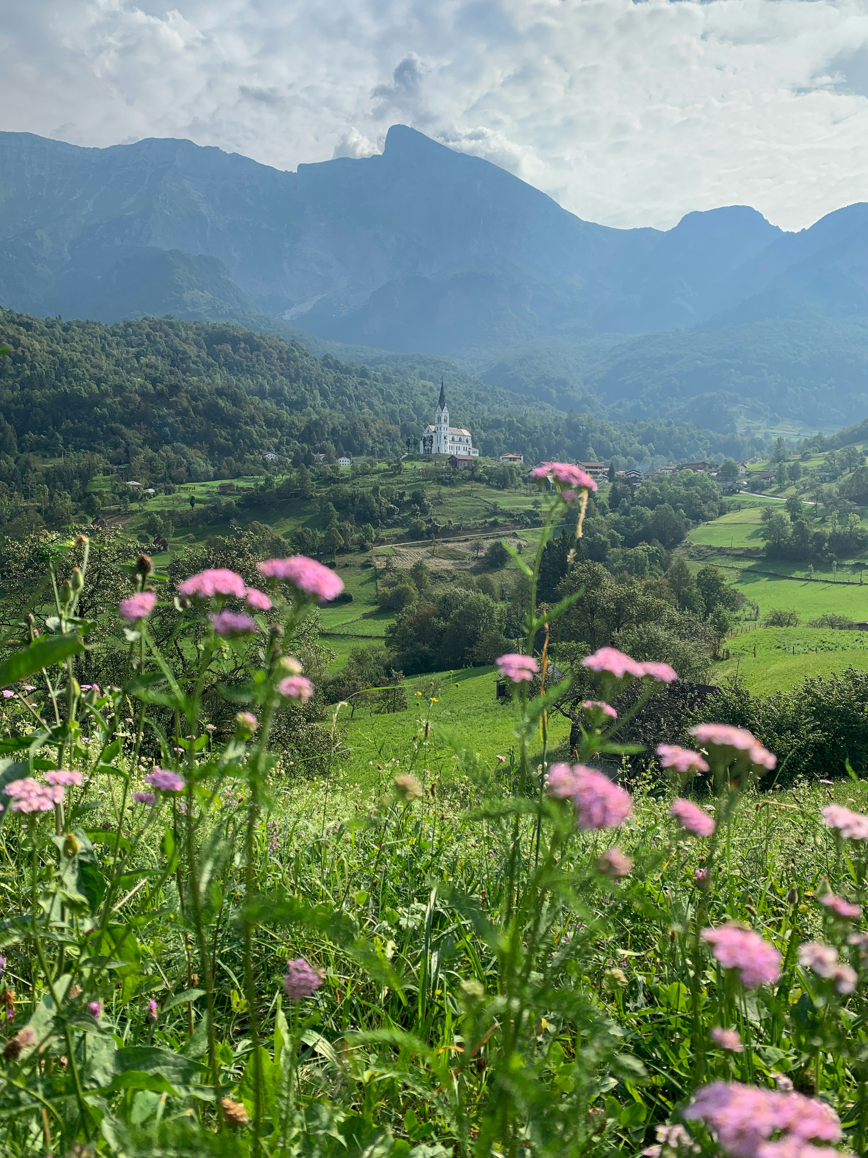 Hilltop Chapel Among Green Valleys and Pink Wildflowers